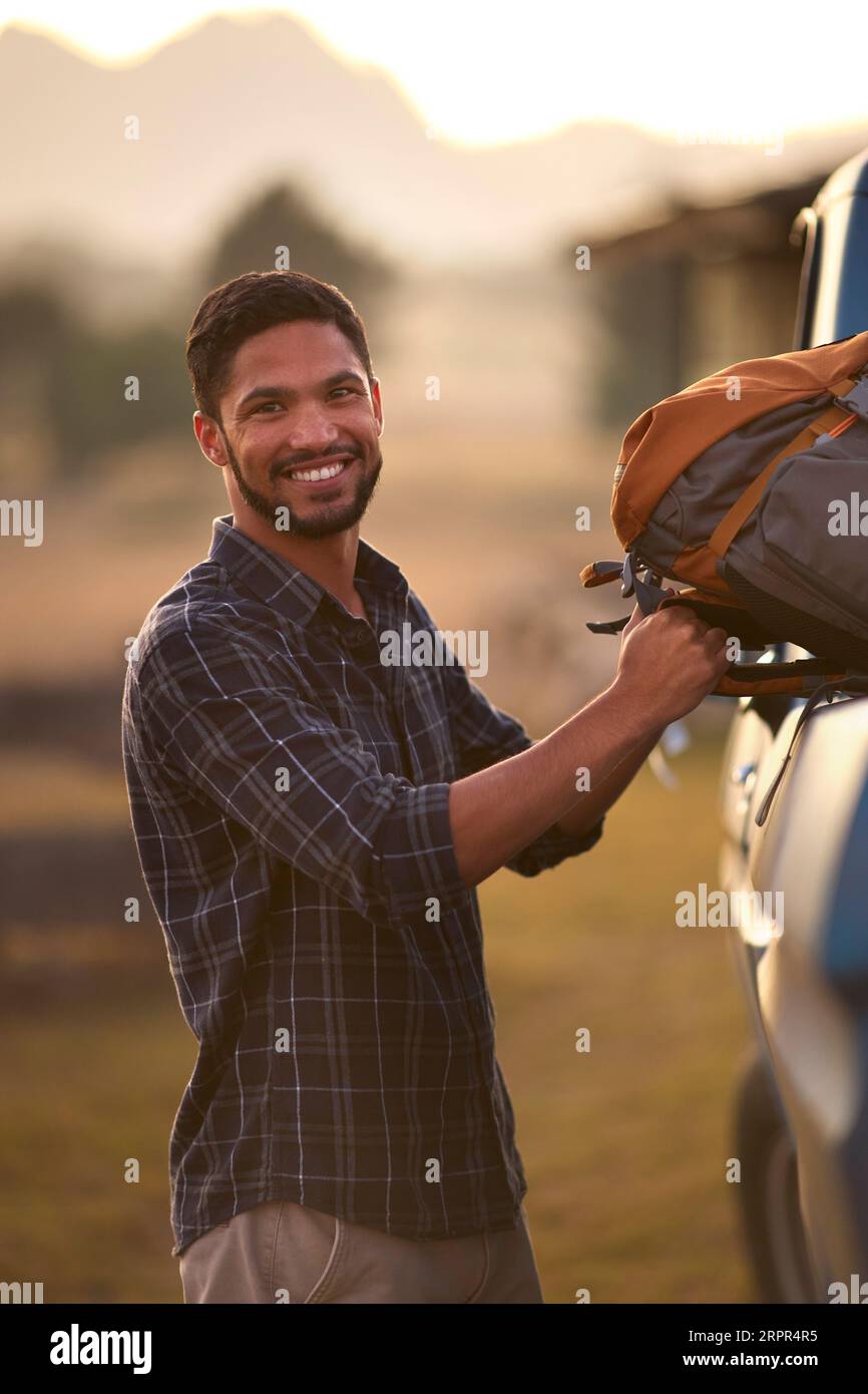 Portrait Of Man Loading Backpack Into Pick Up Truck For Road Trip To ...