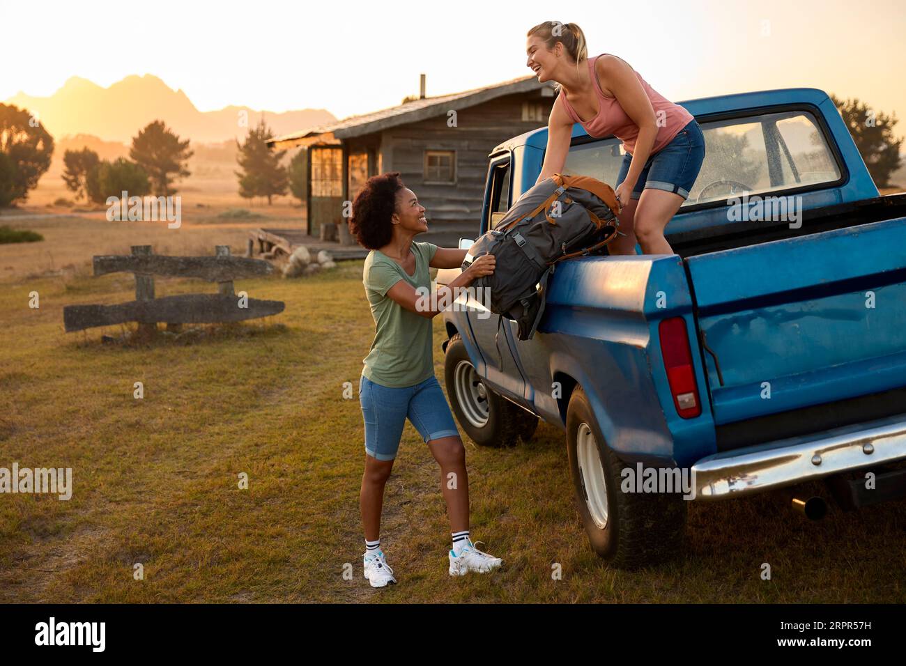 Two Female Friends Unloading Backpack From Pick Up Truck On Road Trip ...