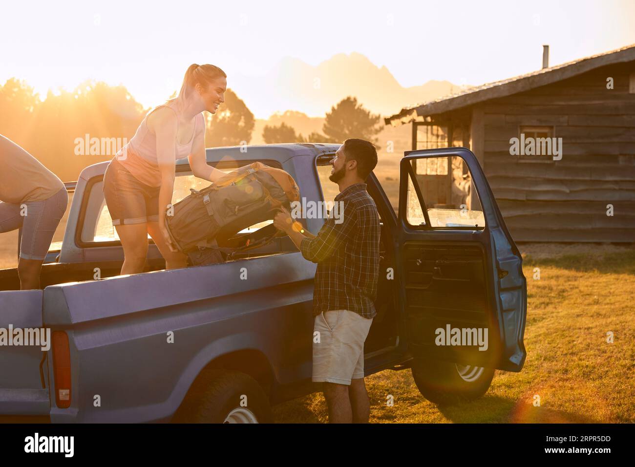 Group Of Friends Unloading Backpack From Pick Up Truck On Road Trip To ...