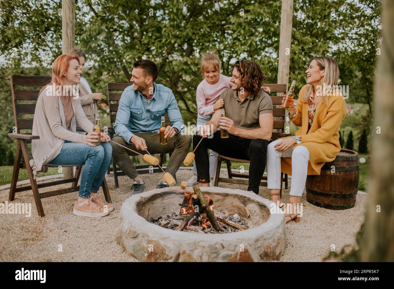 Group of friends having good time and baking corns in the house ...