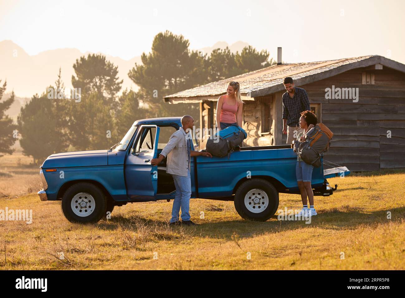 Group Of Friends Unloading Backpack From Pick Up Truck On Road Trip To ...