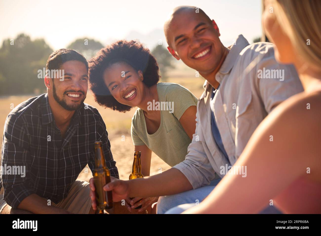 Group Of Friends On Vacation Sitting On Porch Of Countryside Cabin ...