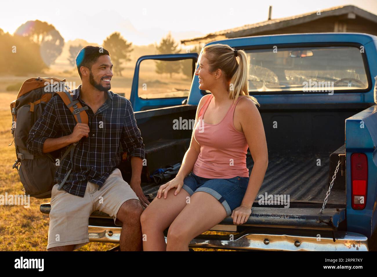 Couple Sitting On Tailgate Of Pick Up Truck With Rucksack On Road Trip ...
