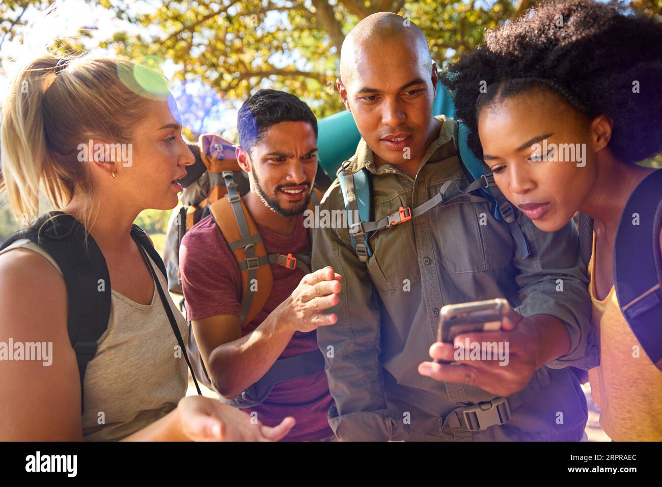 Group Of Friends With Backpacks Using GPS On Mobile Phone On Vacation Hiking In Countryside ...