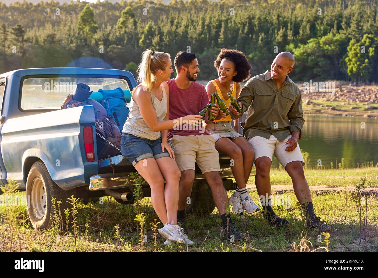 Group Of Friends With Backpacks In Pick Up Truck On Road Trip By Lake ...