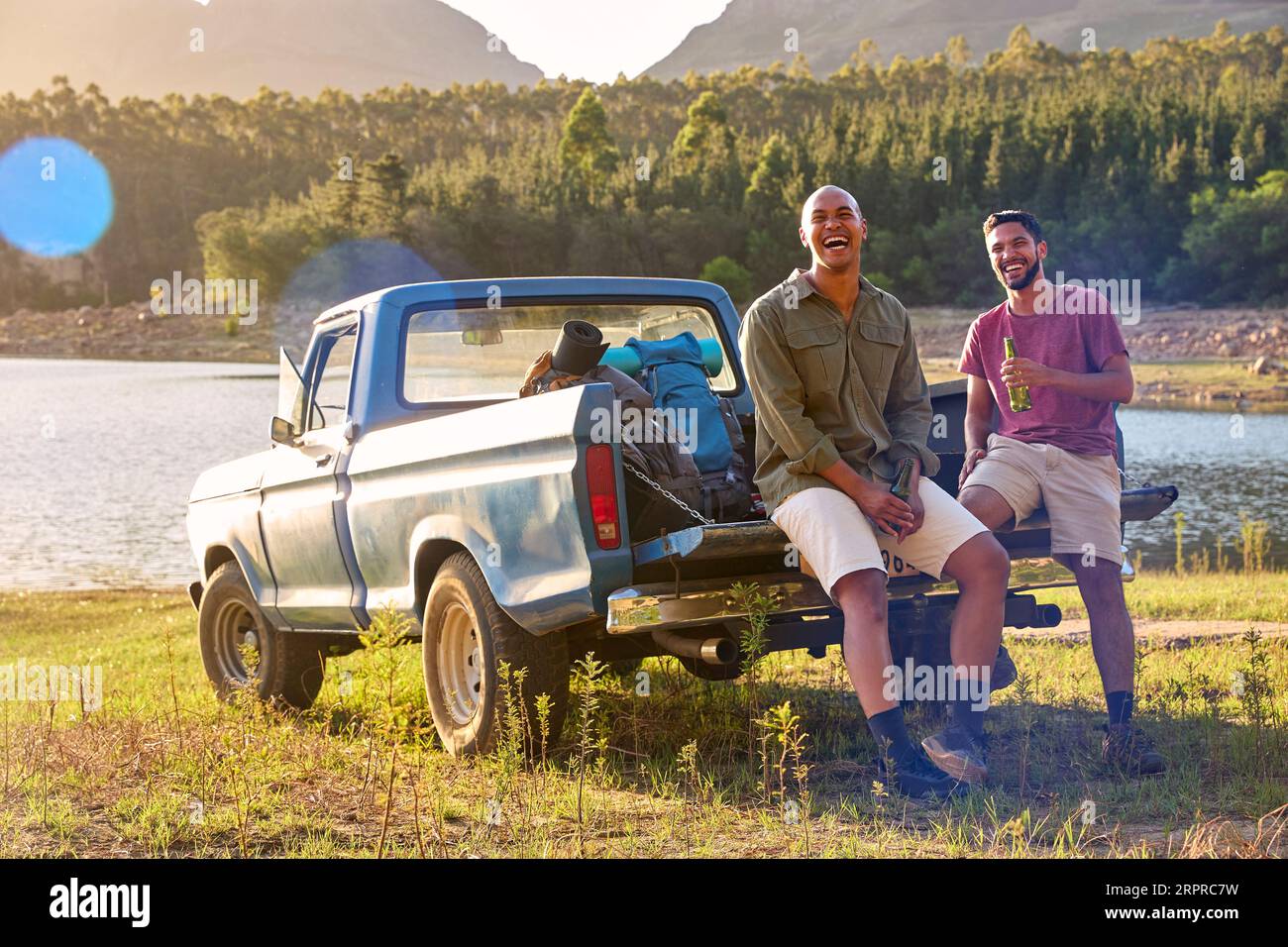Two Male Friends With Backpacks In Pick Up Truck On Road Trip By Lake ...