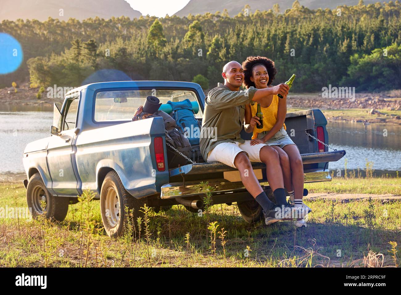 Couple With Backpacks In Pick Up Truck On Road Trip By Lake Drinking ...