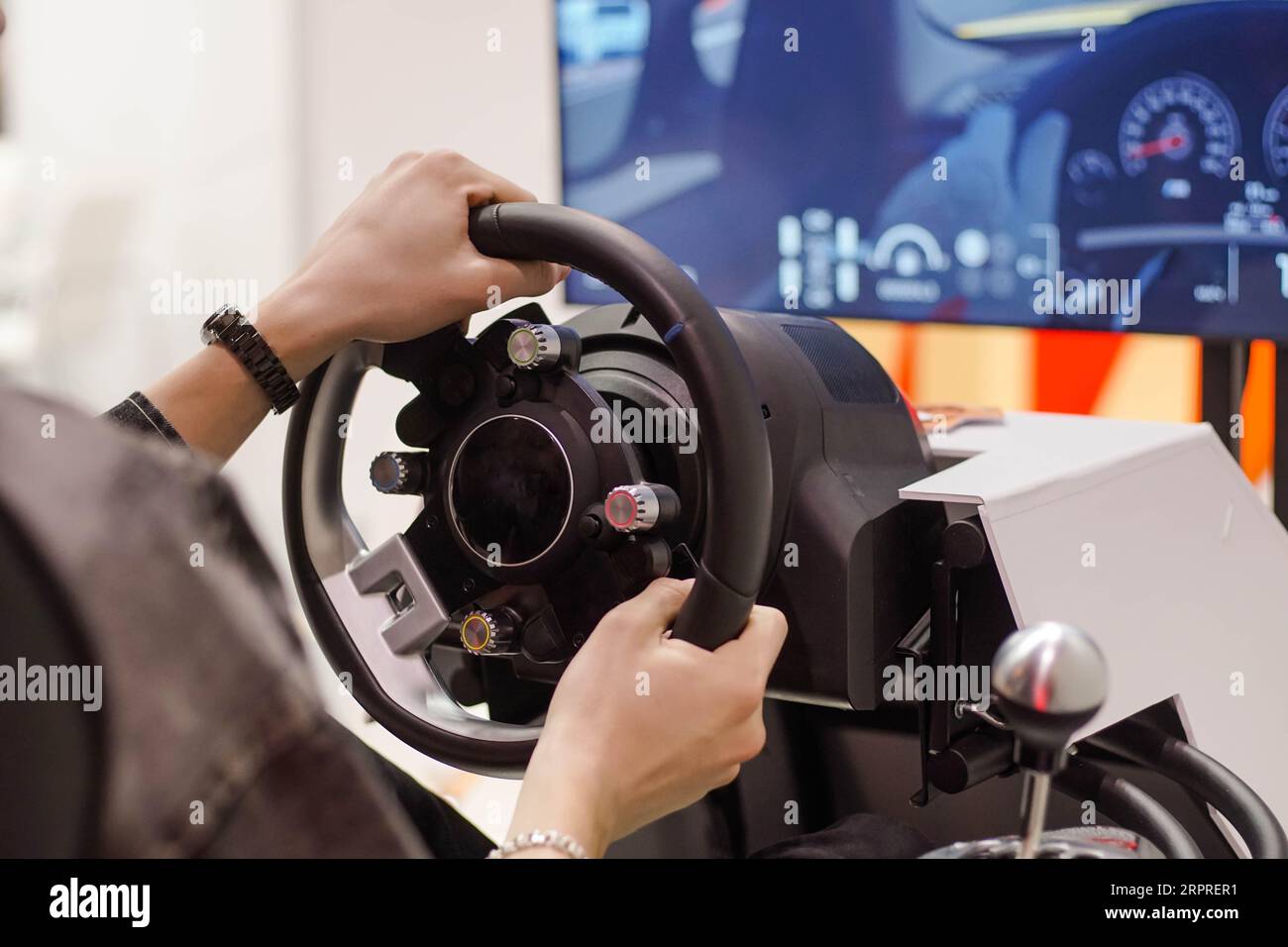 Teen man playing racing simulator game with big screen monitor in theme ...