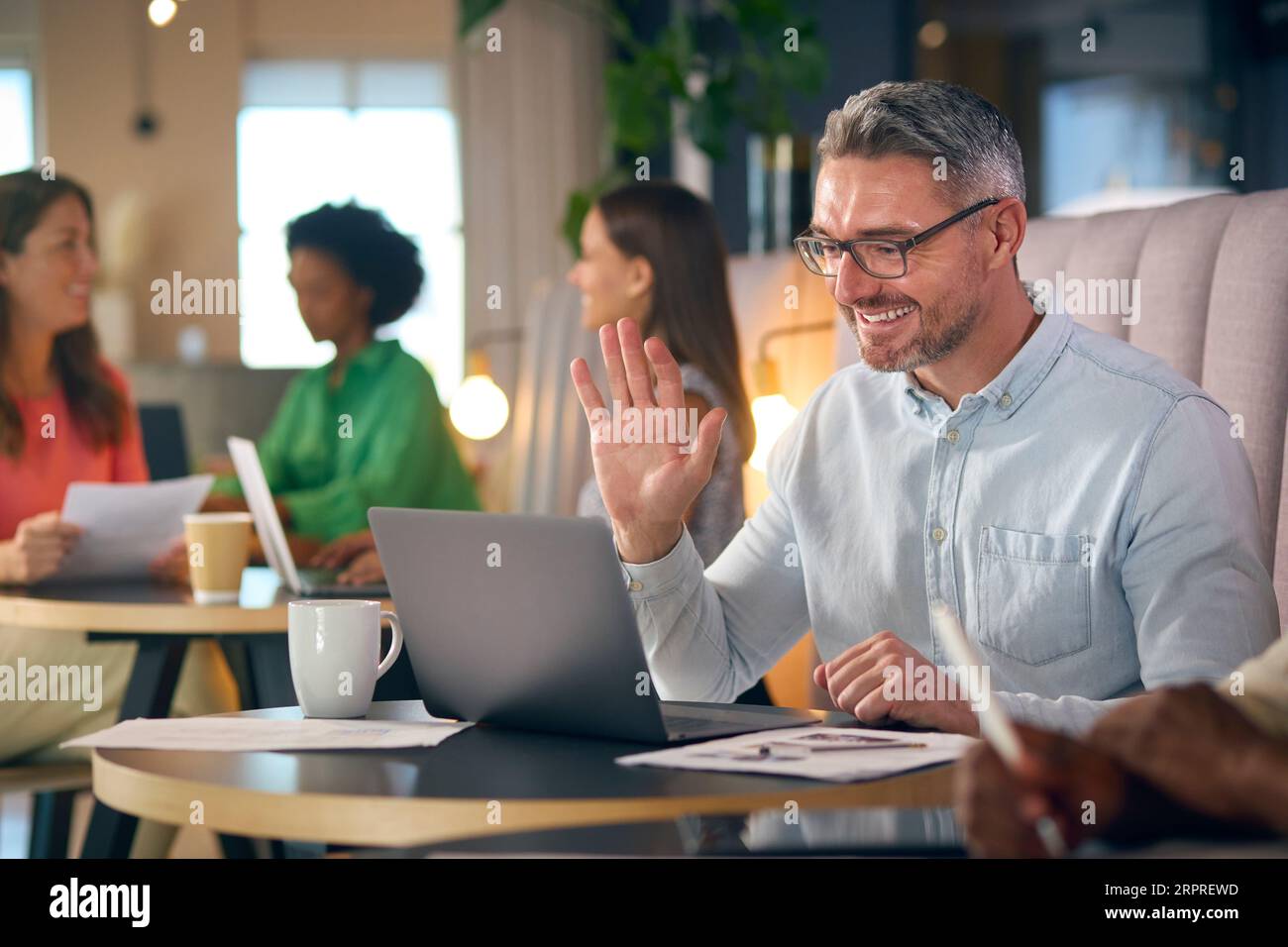 Mature Businessman Making Video Call On Laptop In Informal Seating Area ...