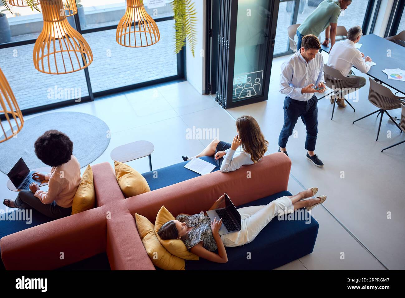 Overhead View Of Modern Open Plan Office With Staff Working Around Table And Breakout Seating ...