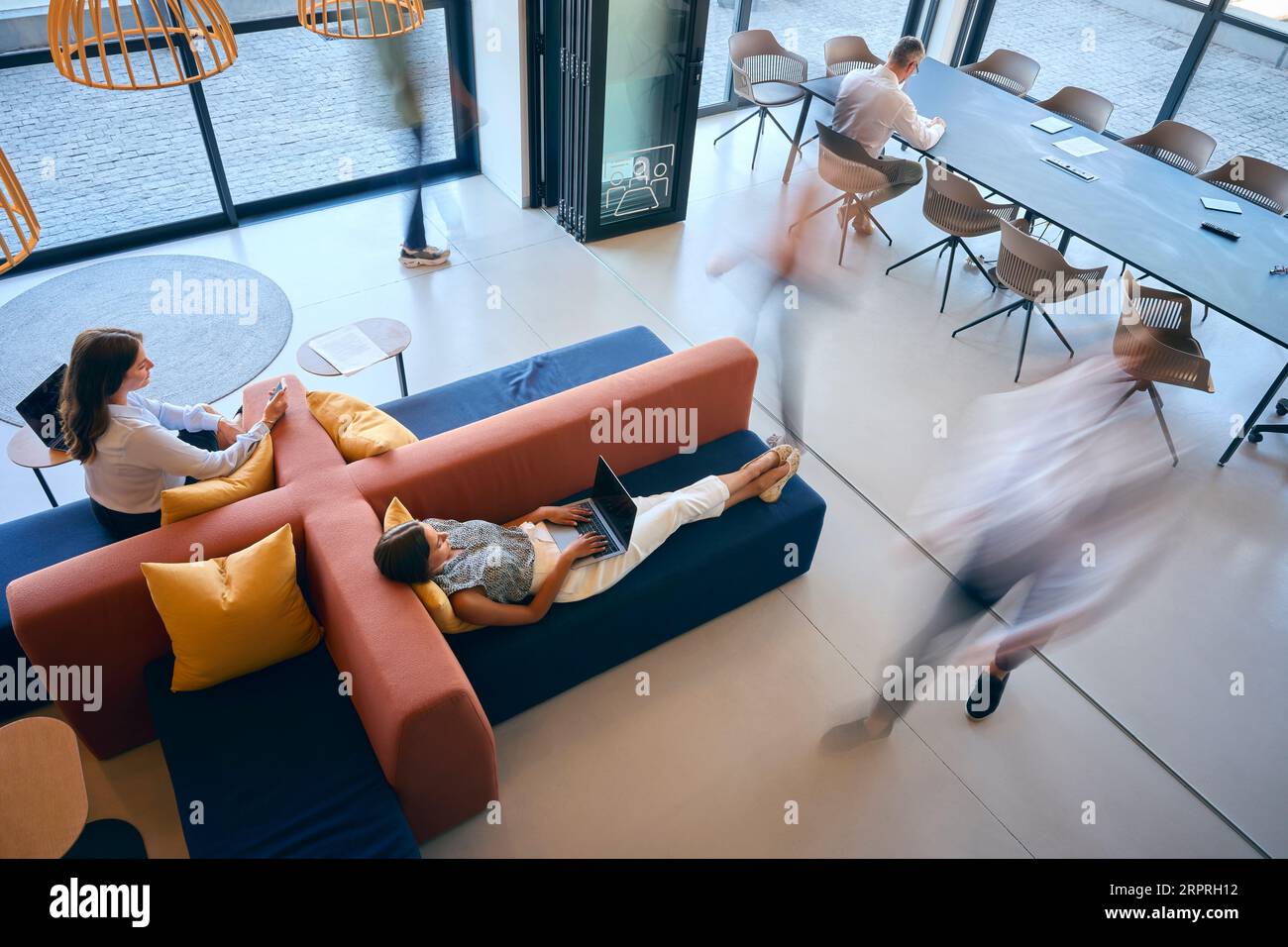 Overhead View Of Modern Open Plan Office With Staff Working Around Table And Breakout Seating ...