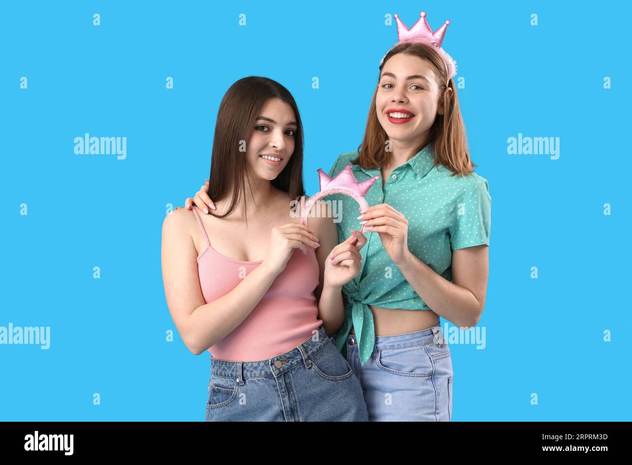 Female friends with crowns on blue background Stock Photo - Alamy