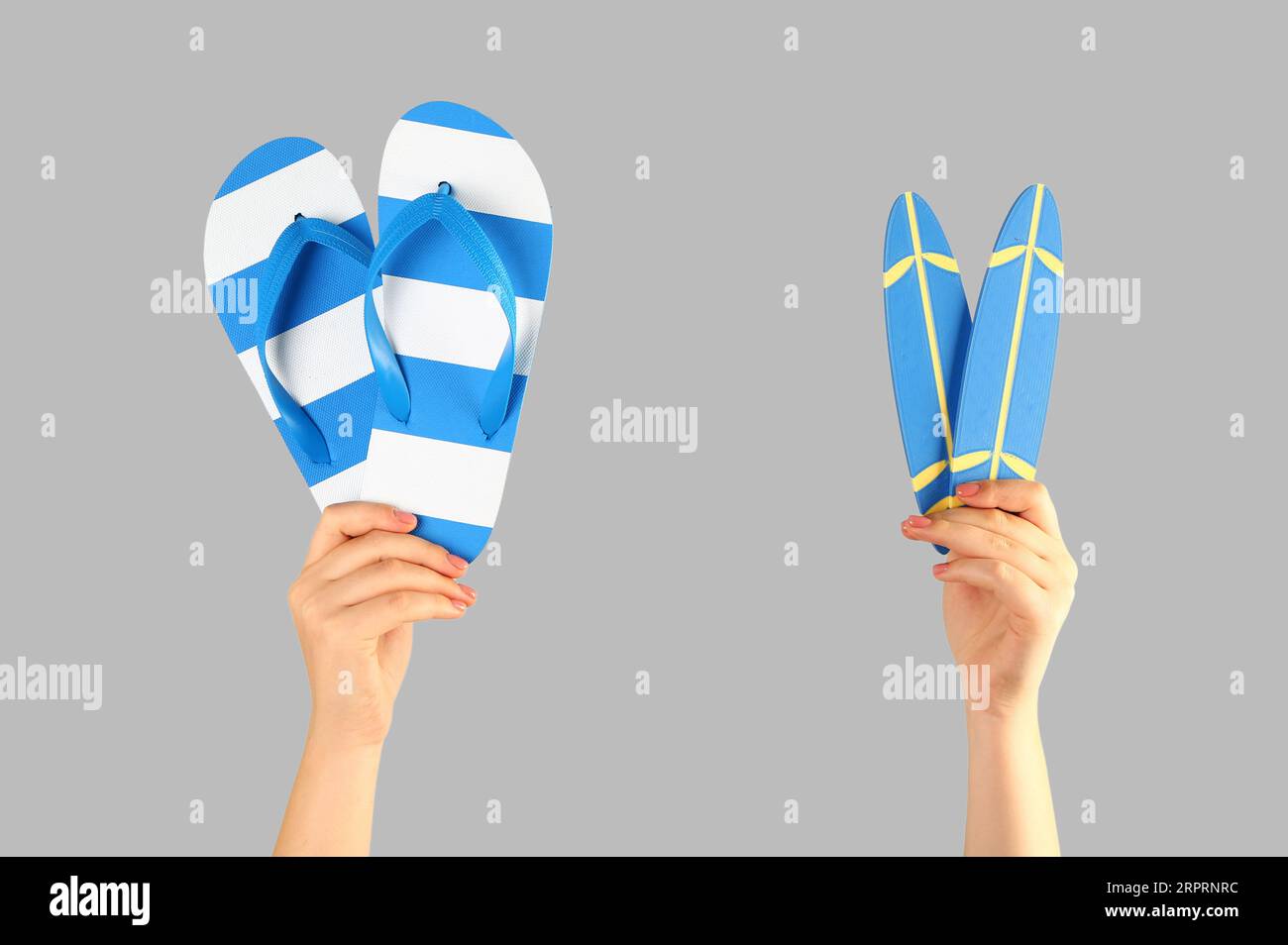 Female hands with mini surfboards and flip flops on grey background ...