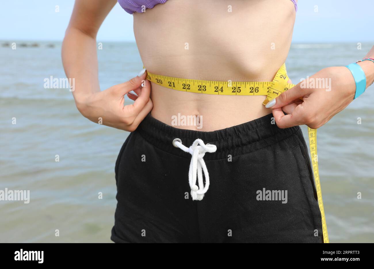 young girl measuring her waist with the yellow measuring tape with ...
