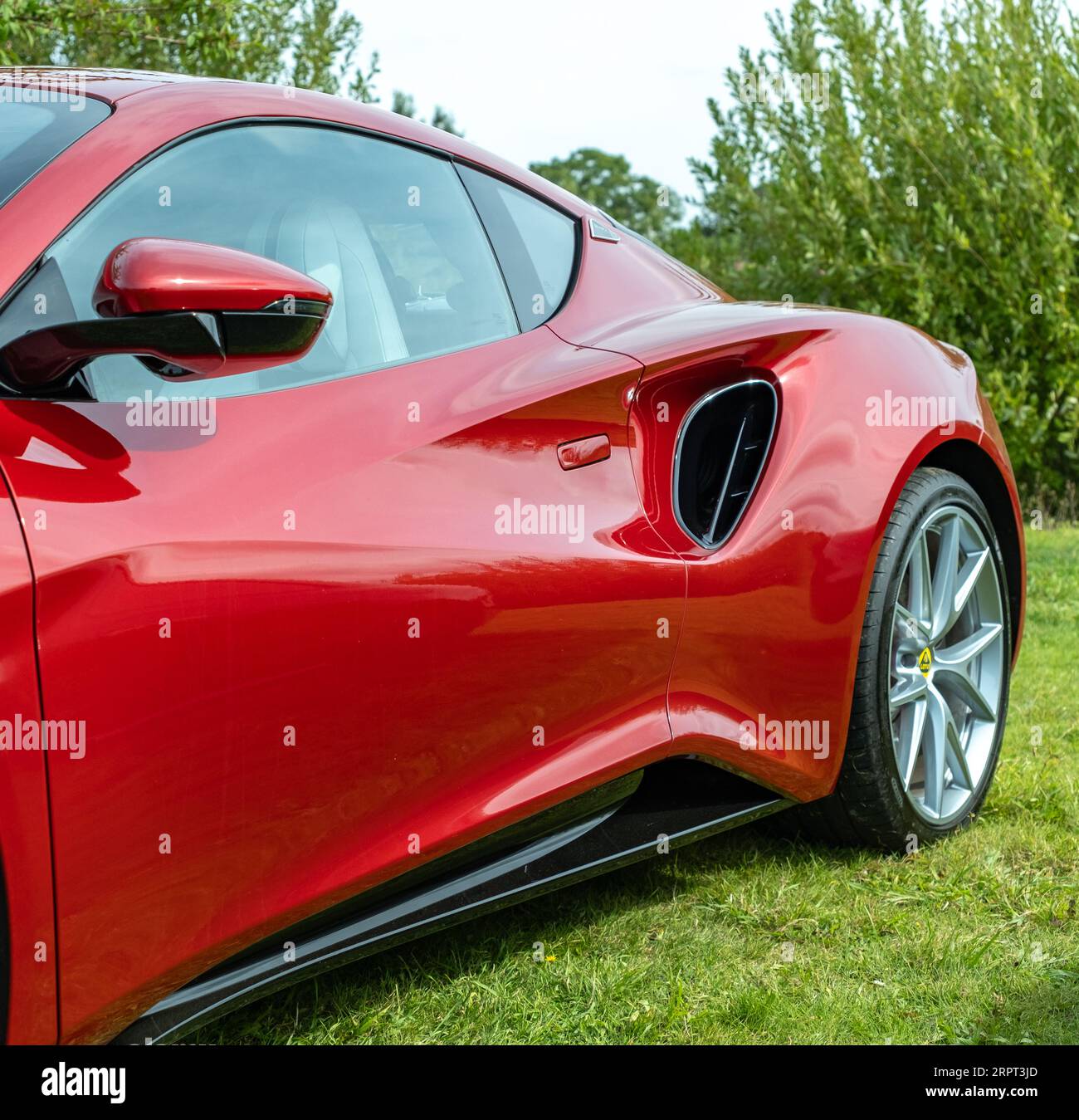 Side on view of a red supercar on display at an outdoor supercar show ...