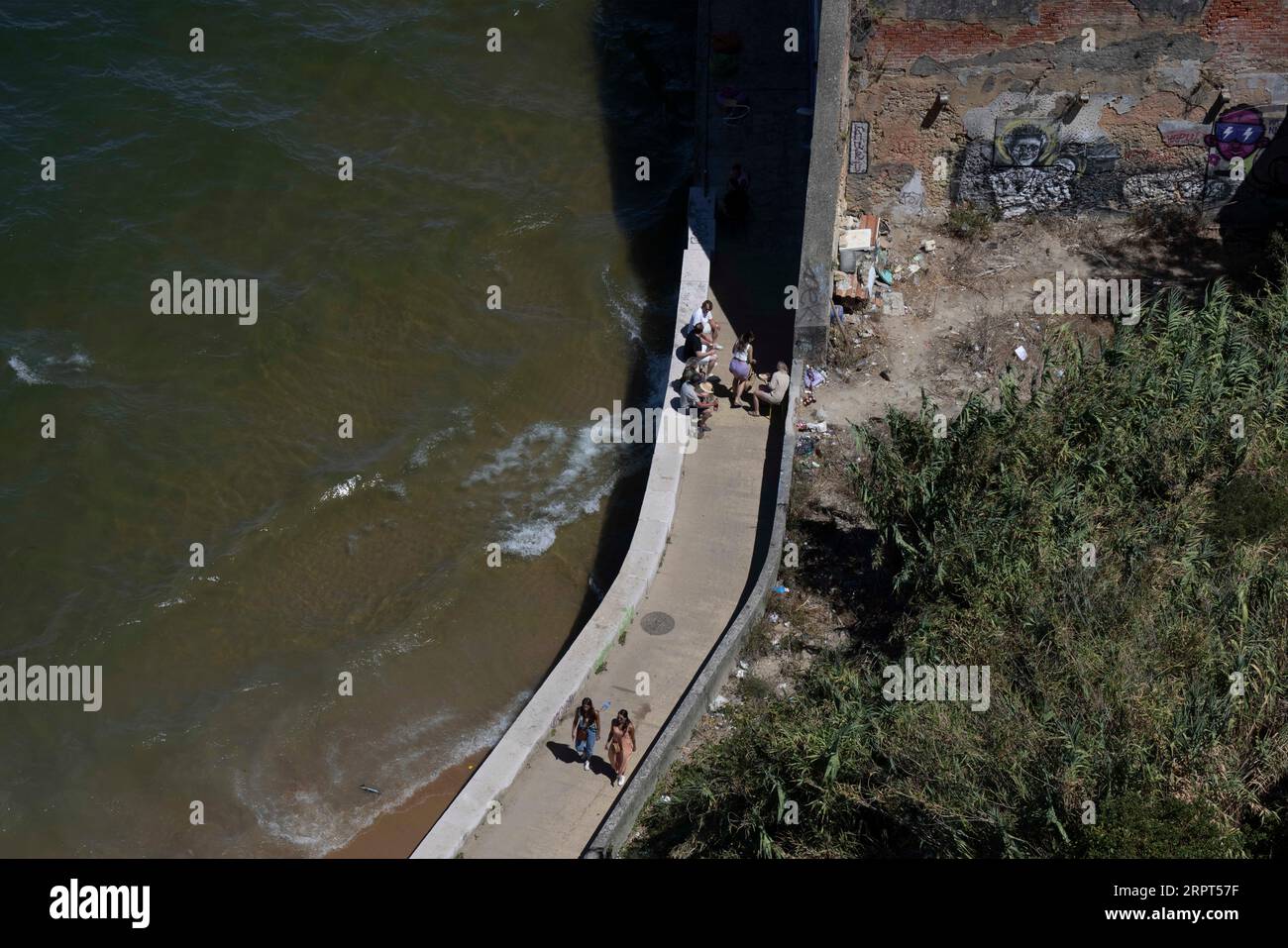 People seen walking along a promenade near the Tejo river in the town ...