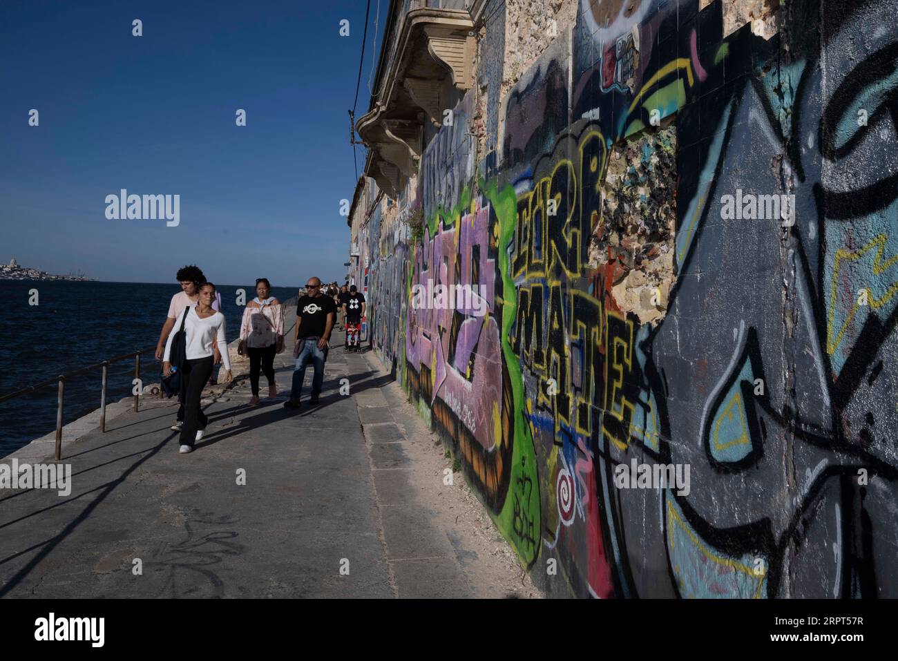 People seen walking along a promenade near the Tejo river in the town ...