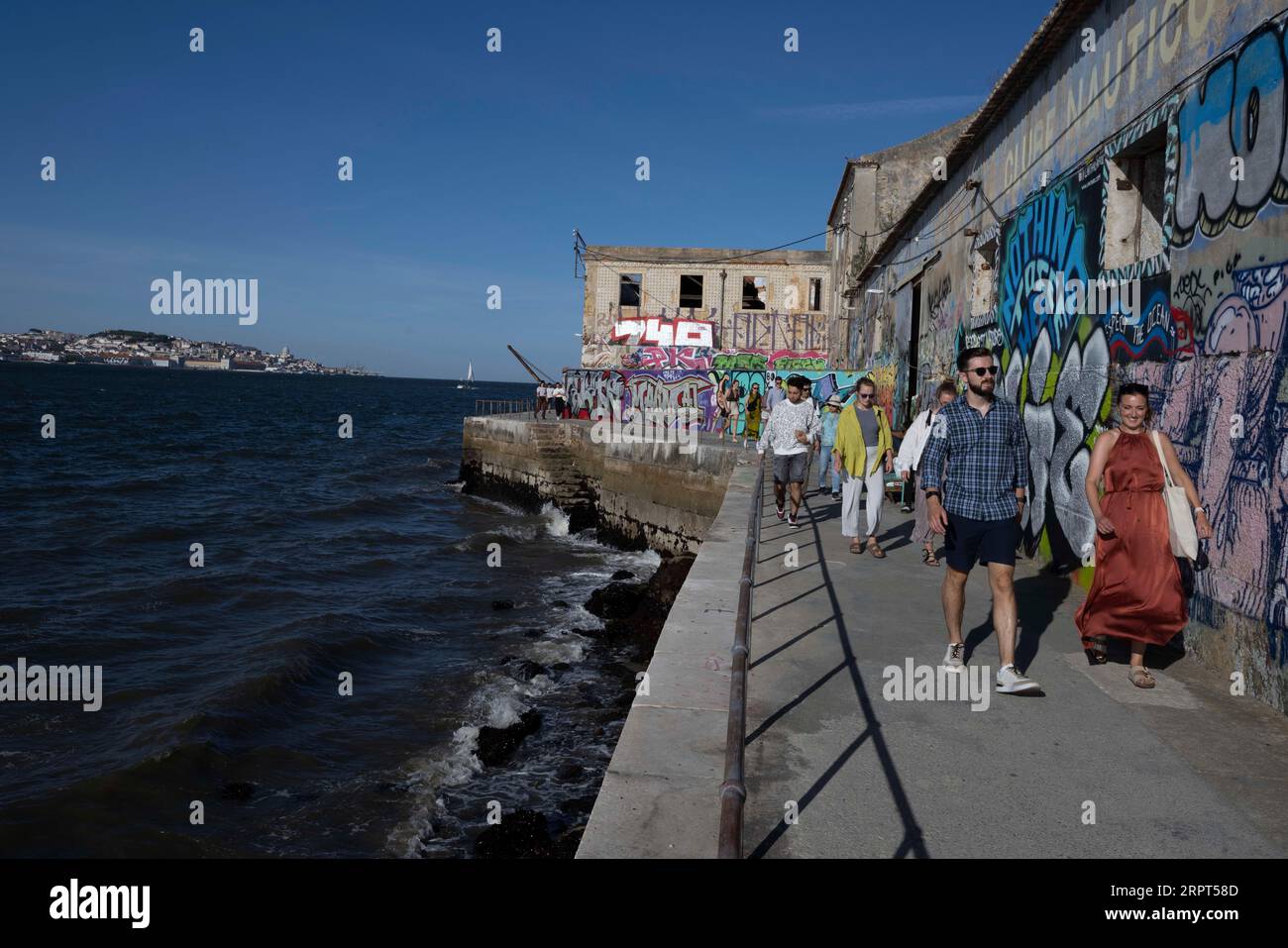 People seen walking along a promenade near the Tejo river in the town ...
