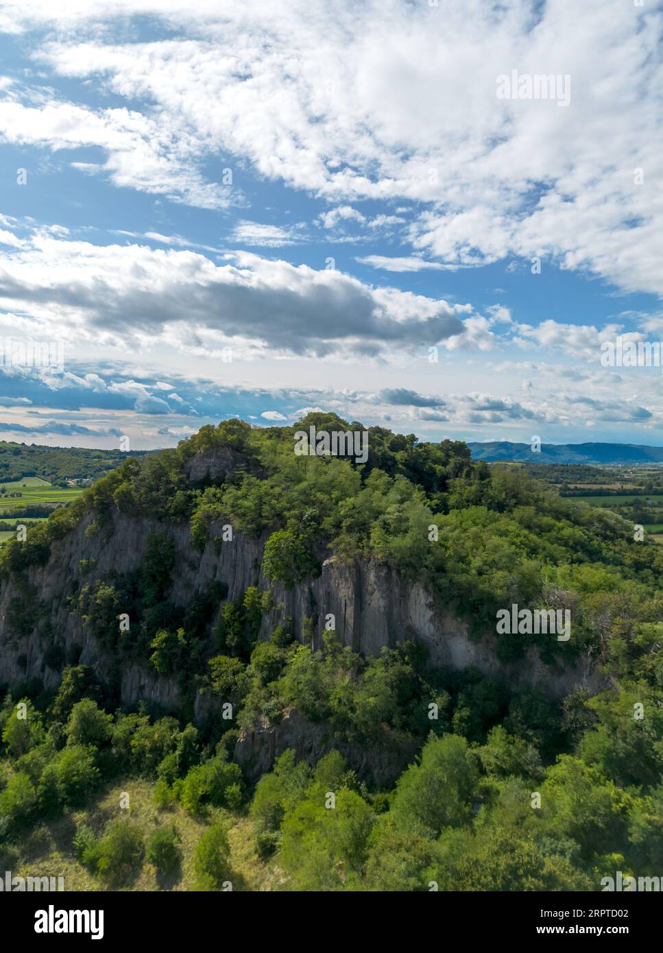 Aerial view of steep cliff on a hill with green trees growing on top ...