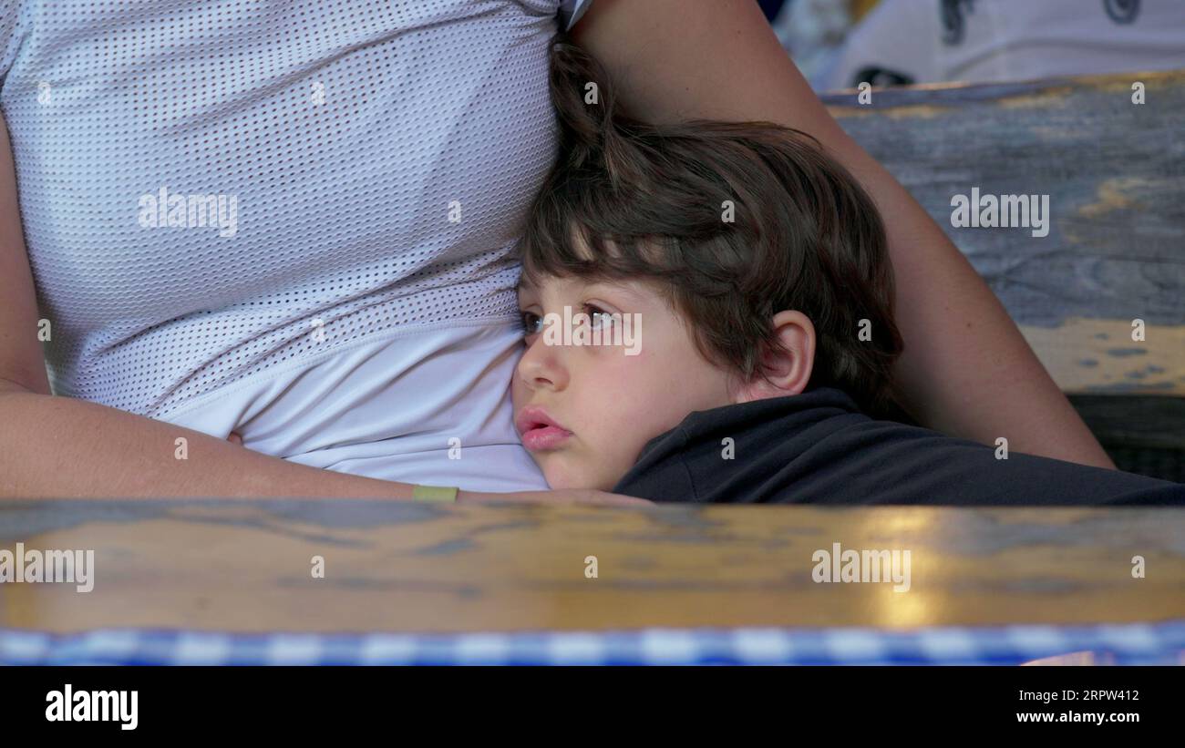 Bored little boy clinging to mother's body with nothing to do, child struggles with boredom ...