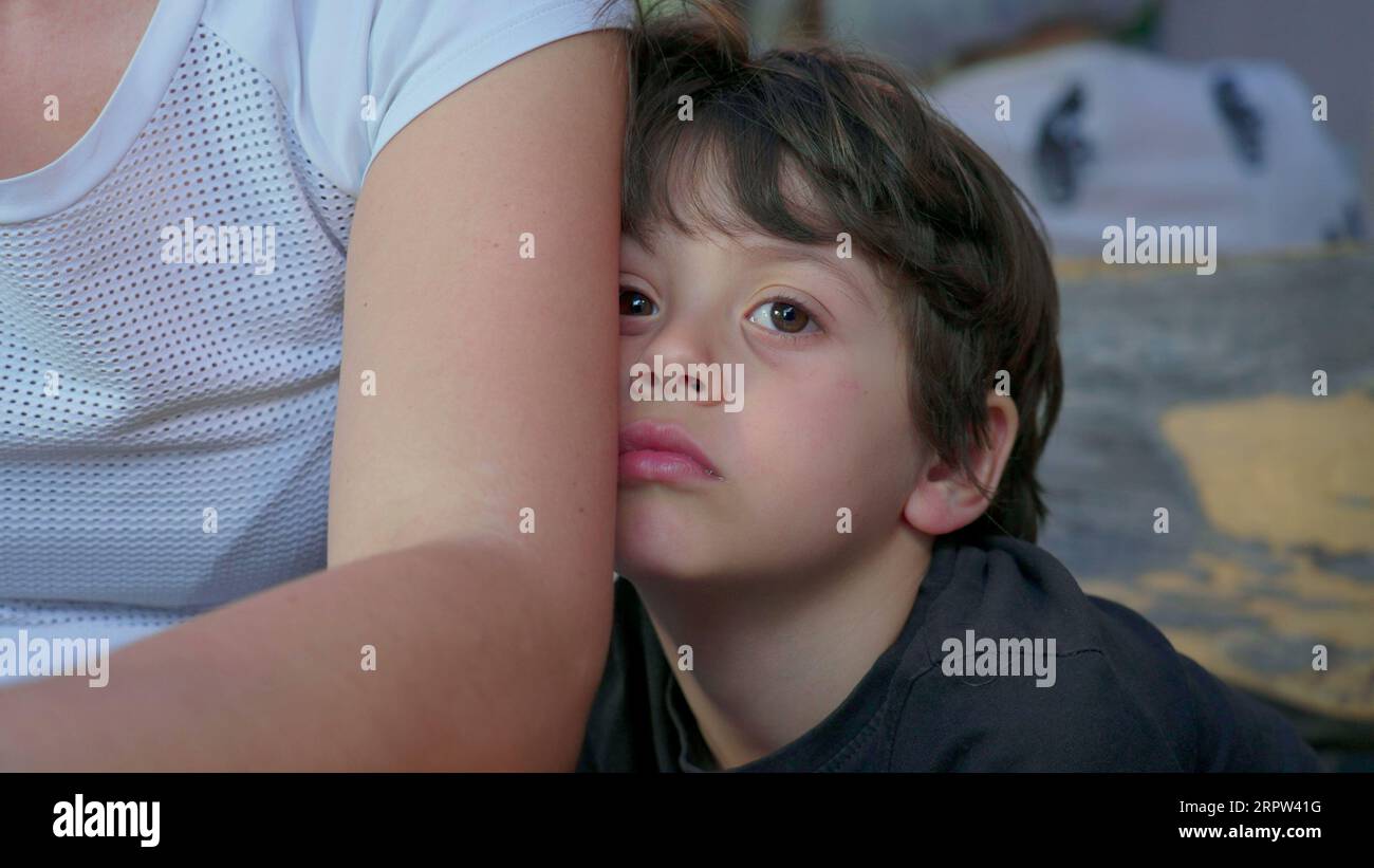 Bored child hiding behind mother's arm feeling boredom, close-up of shy kid with nothing to do ...