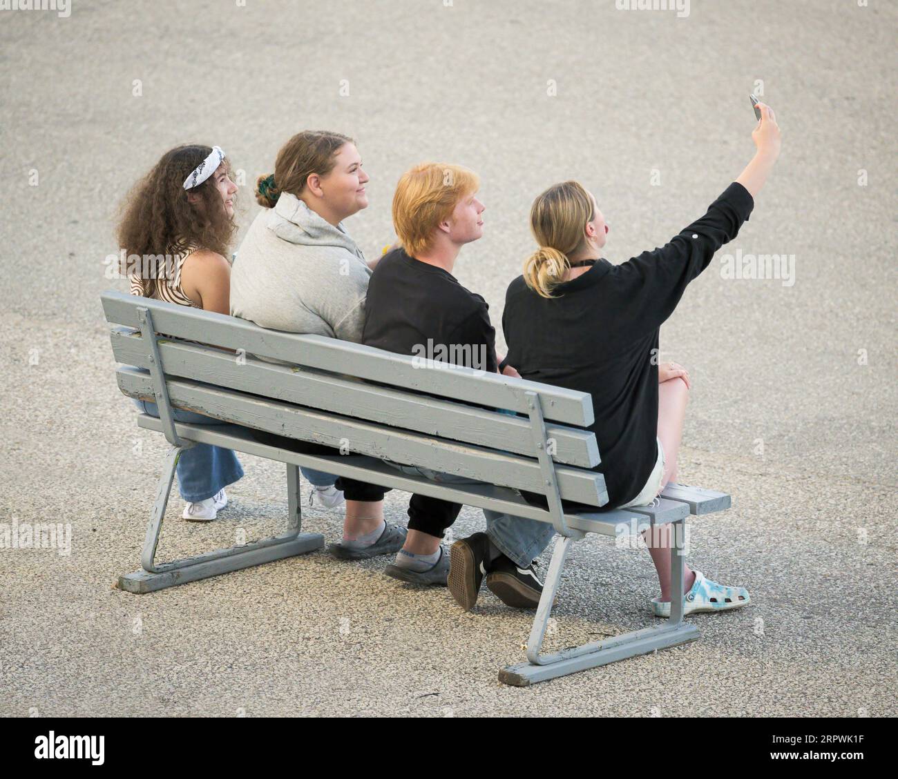Four people on a bench taking a selfie Stock Photo - Alamy