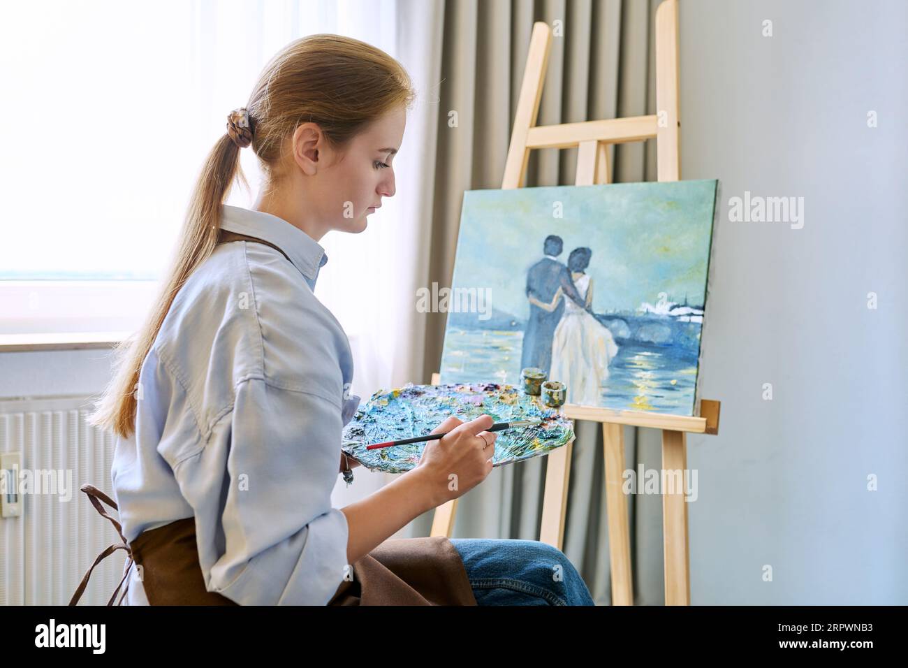 Young pretty female artist painting with acrylics on an easel Stock ...