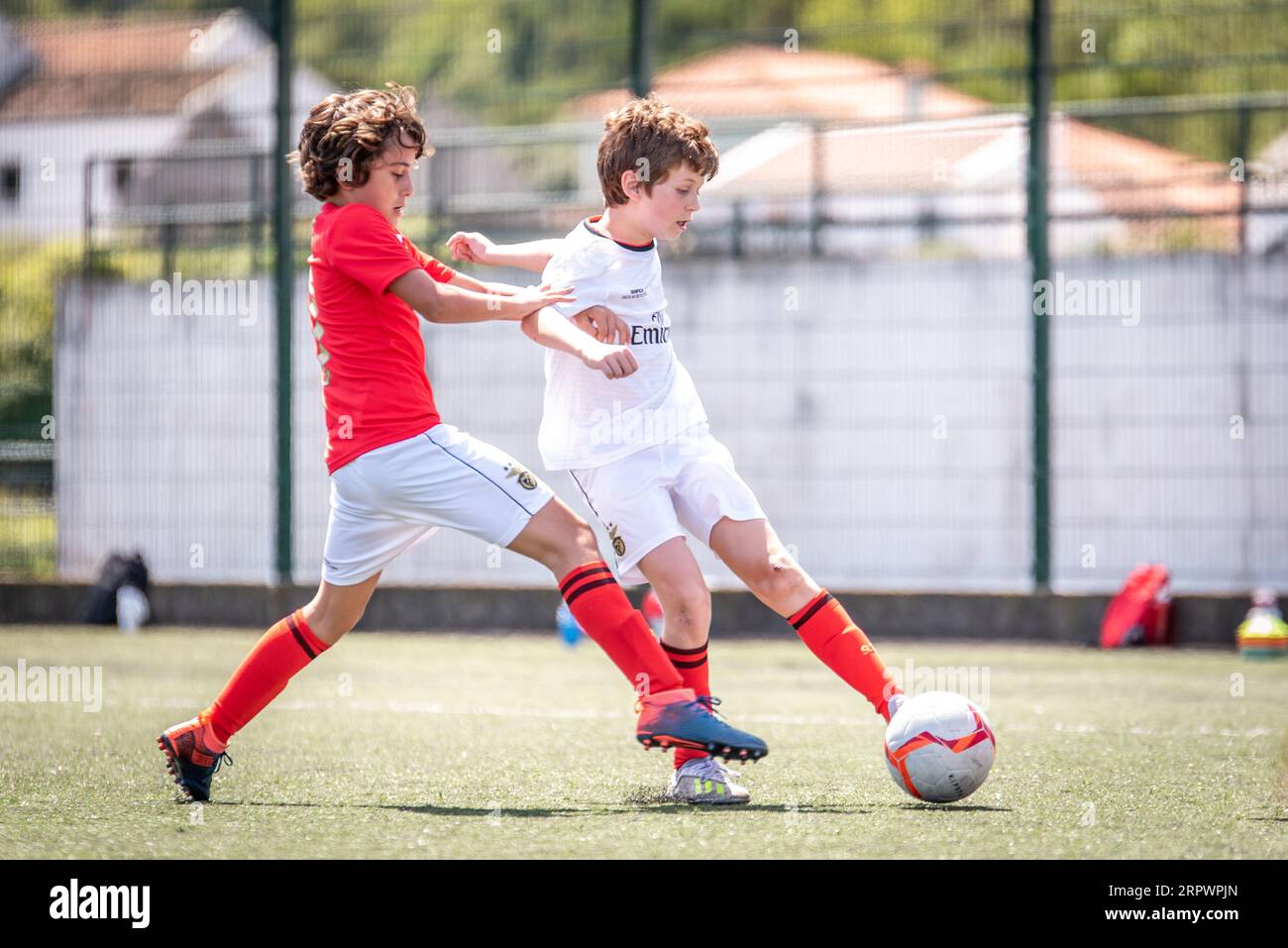 Two pre-teen boys play a game of soccer, one kicking the ball while the ...