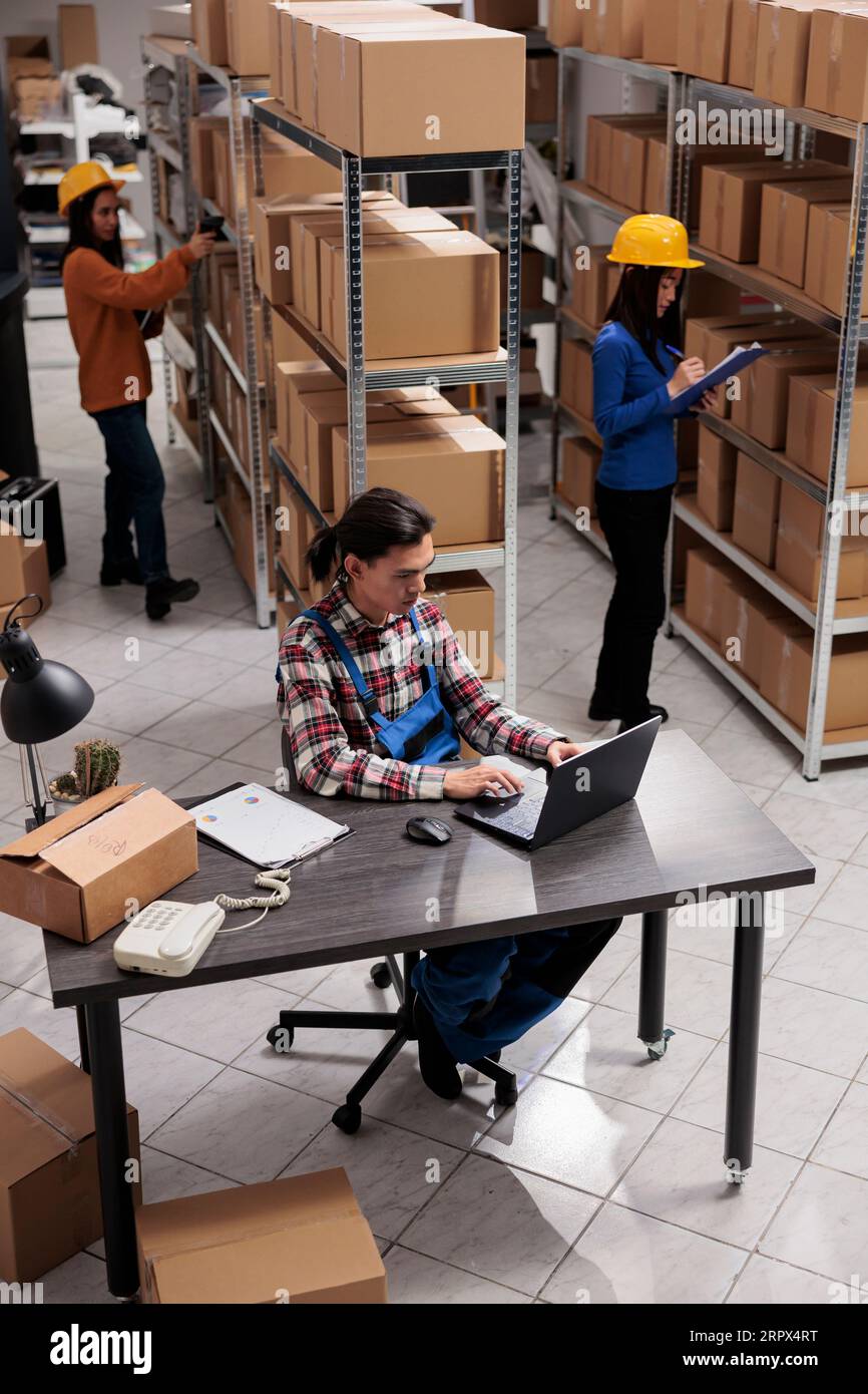 Asian order pickers team handling packages dispatching in warehouse. Storehouse workers ...