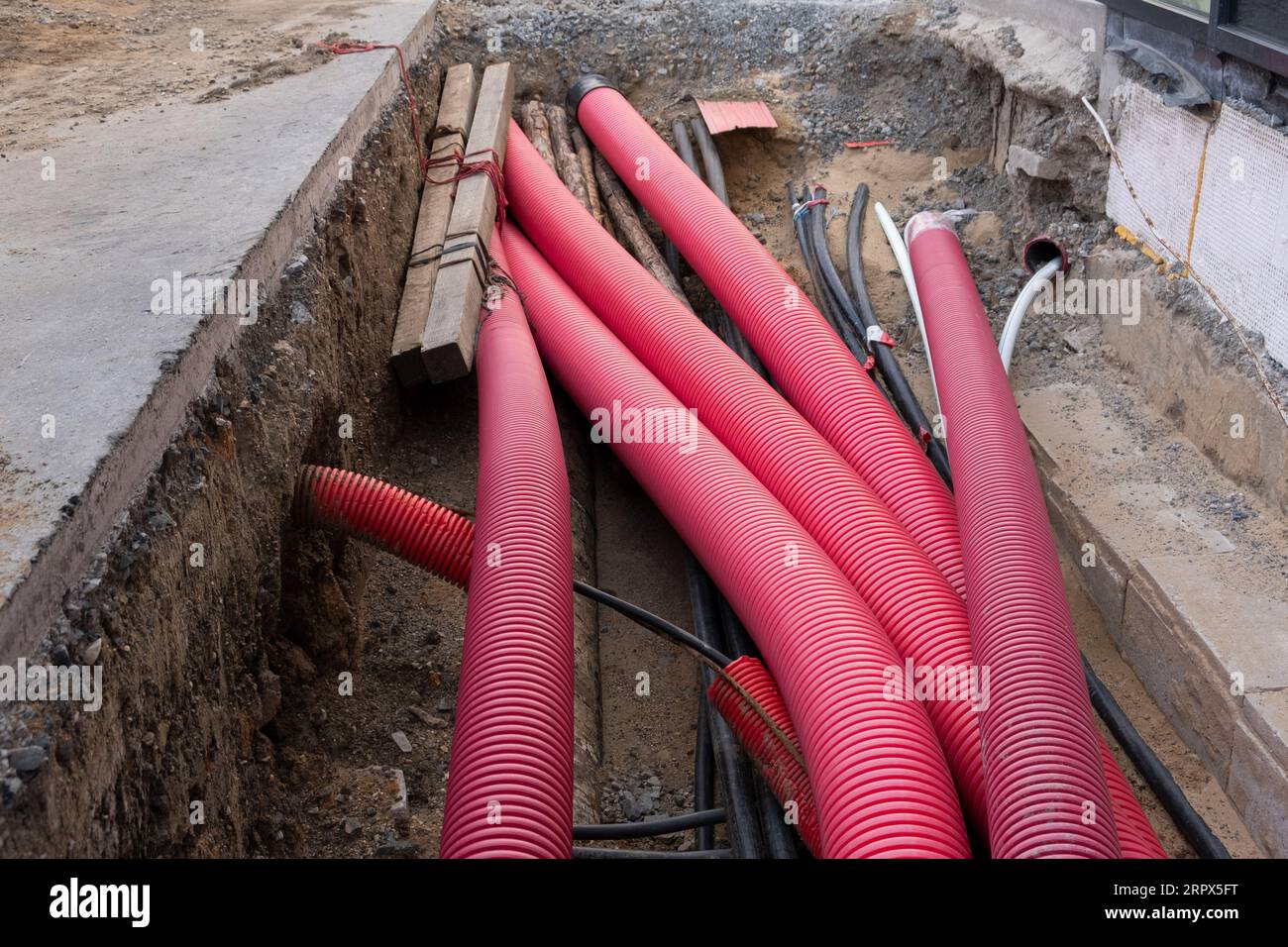 red corrugated pipe are buried underground on the street. underground ...