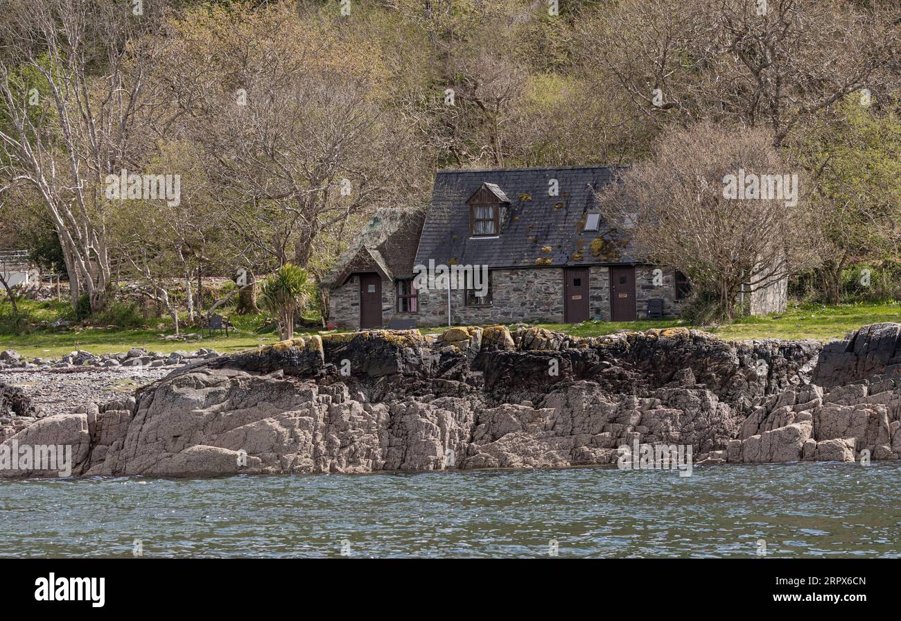 Old stone croft house on the edge of a Loch with brown paint and a ...