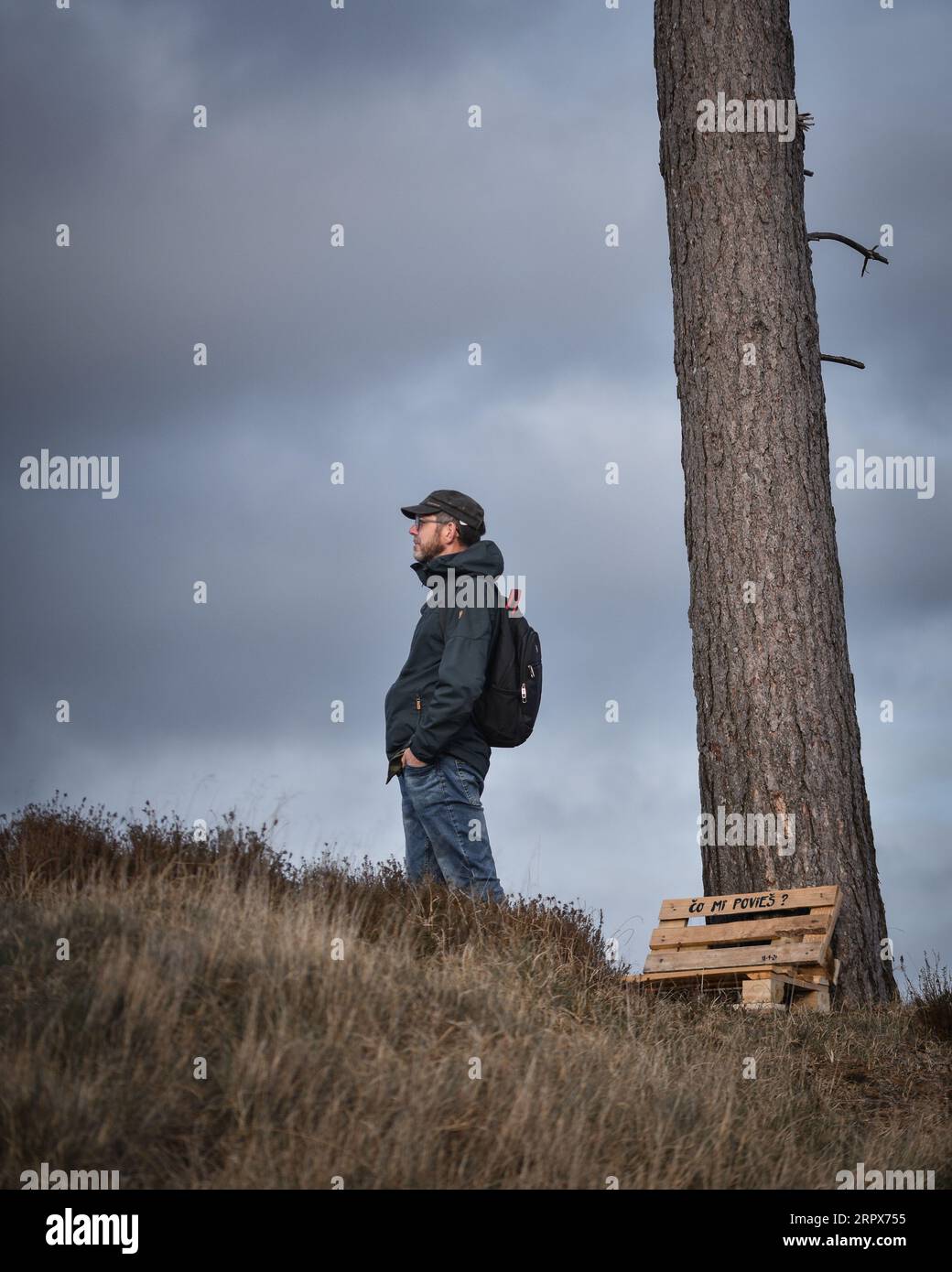Profile view of hiking man with hands in pocket wearing cap and ...