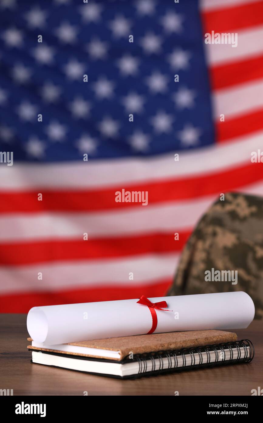 Diploma and notebooks on wooden table against flag of USA. Military ...