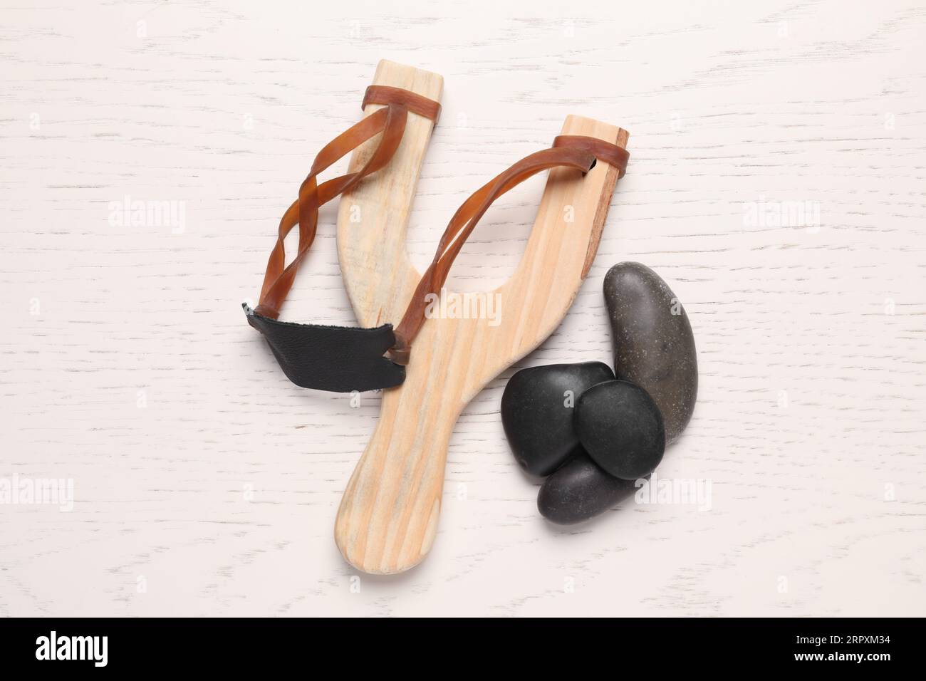 Slingshot with stones on white wooden background, flat lay Stock Photo ...