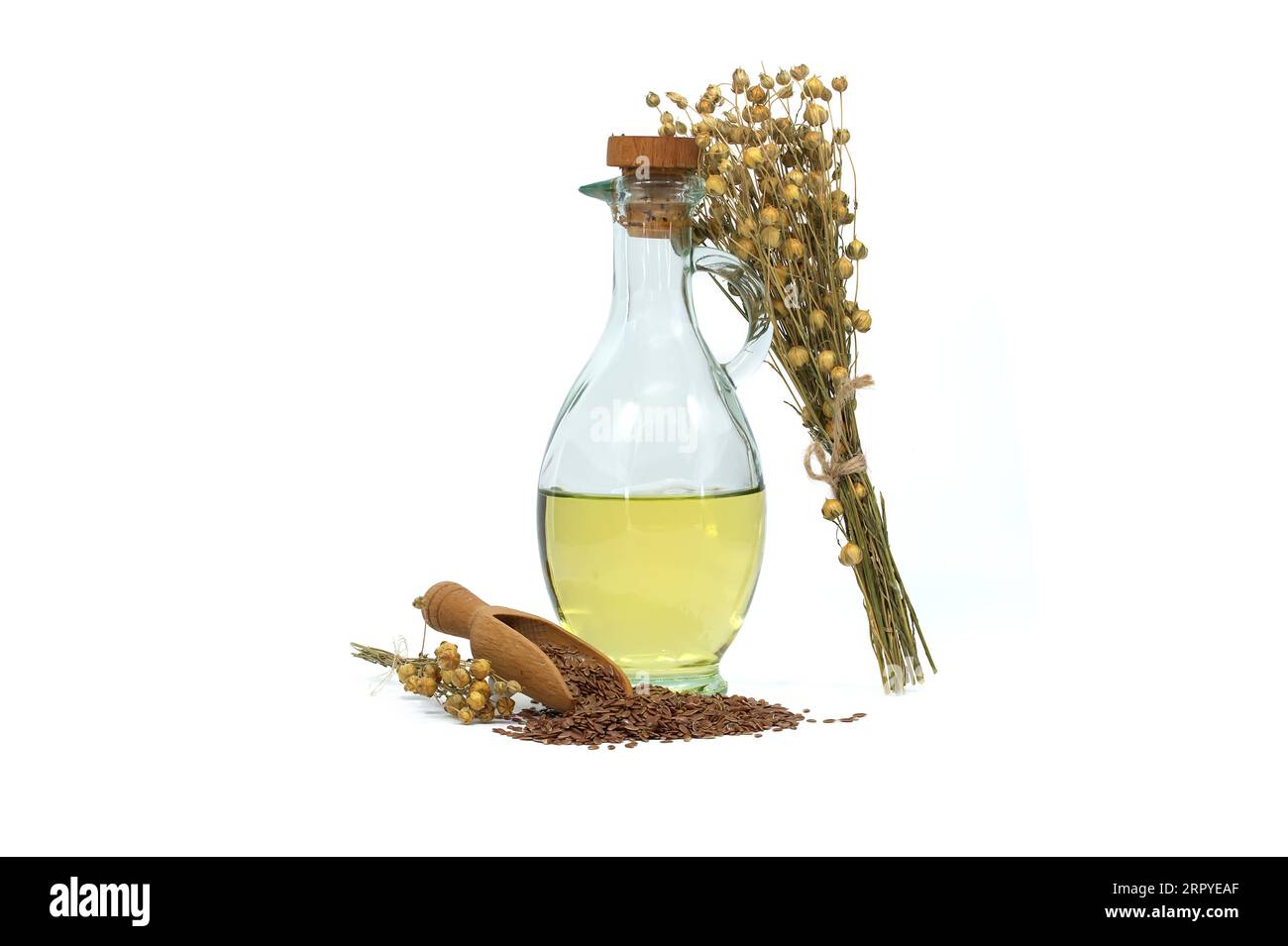 Linseed oil in glass decanter and flax seeds in wooden scoop and bunch of flax plants isolated ...