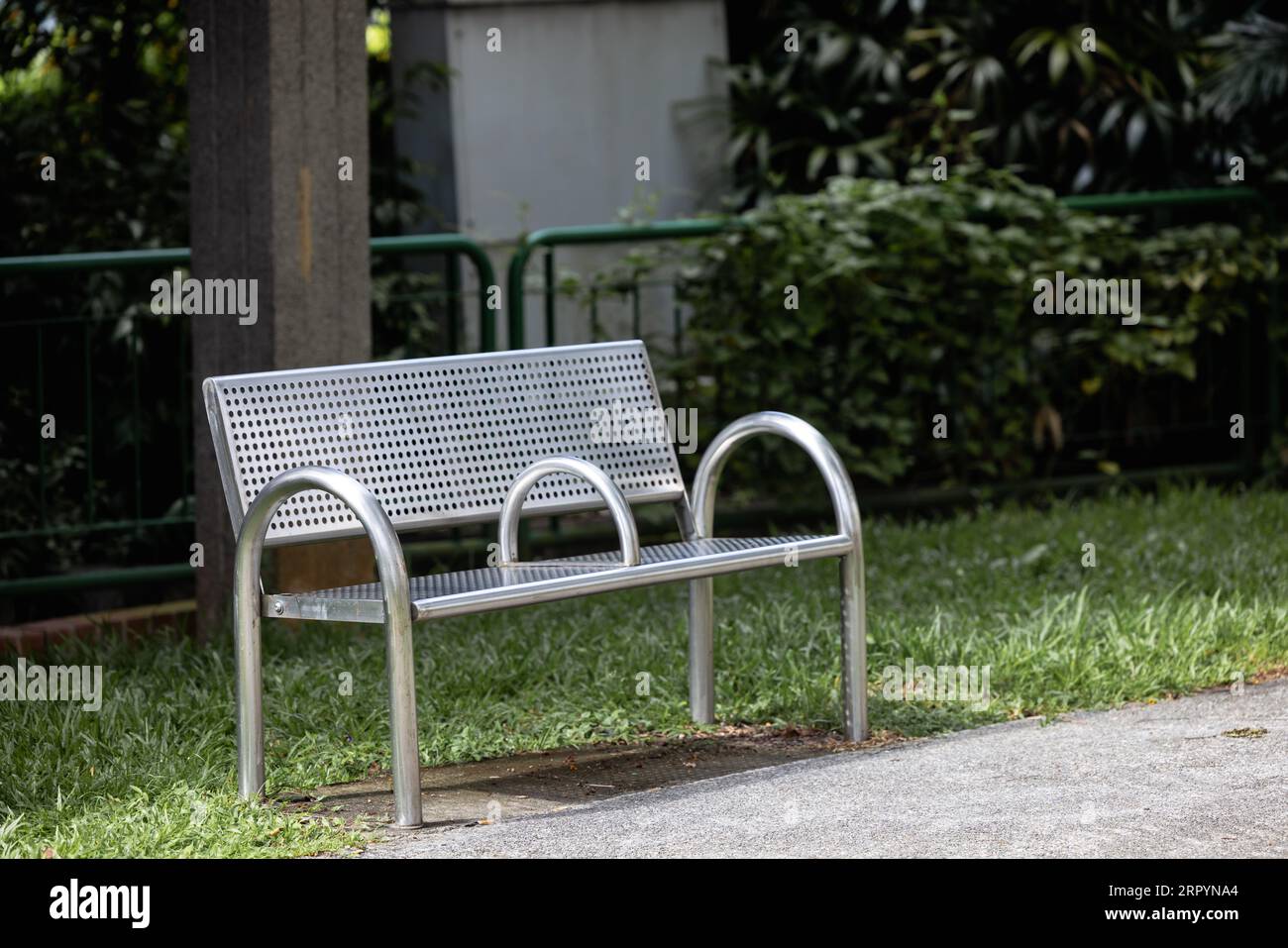 A metal bench stands in the park on the street, there are no people ...