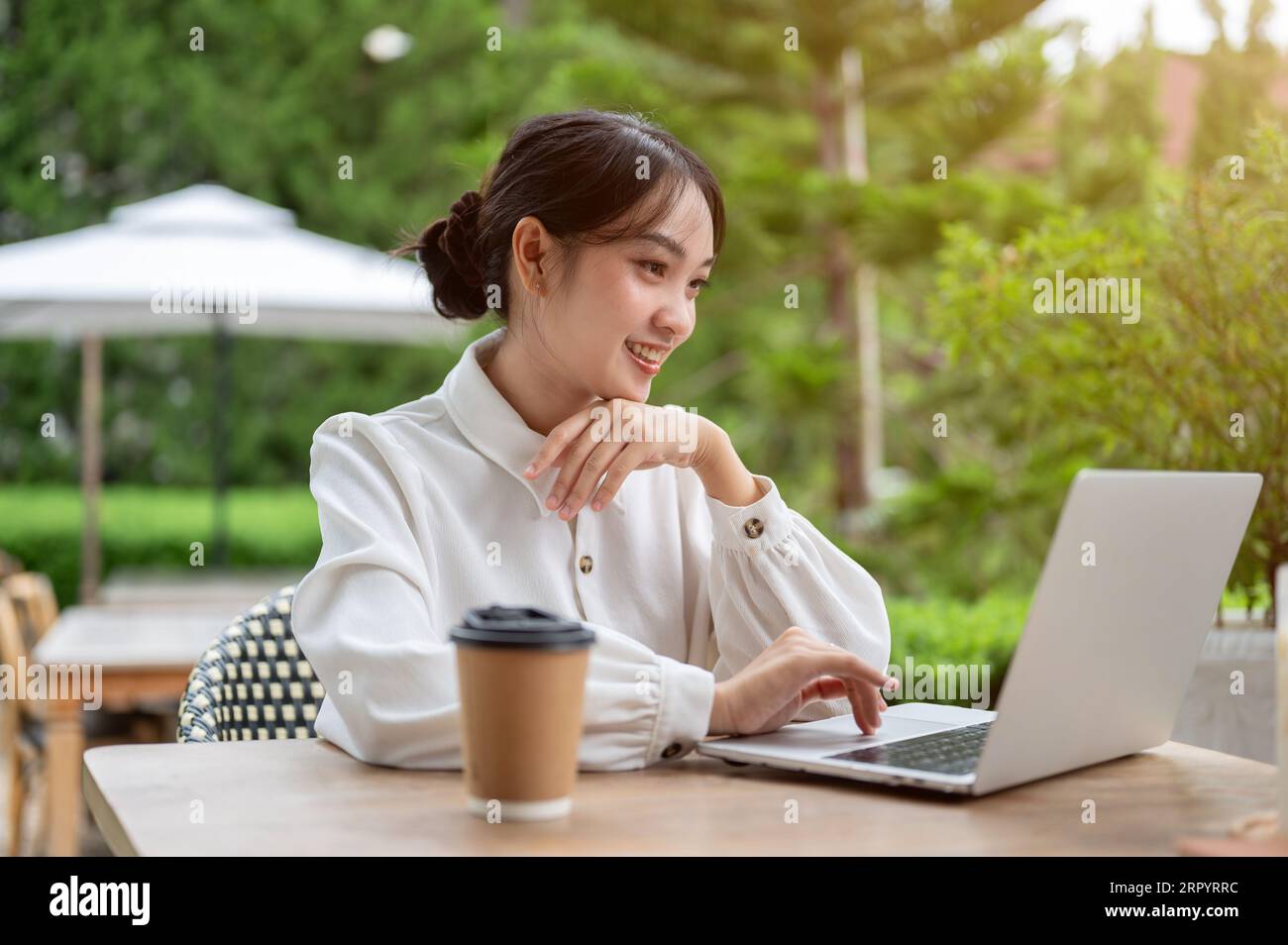 An attractive Asian female freelancer is working remotely at a ...
