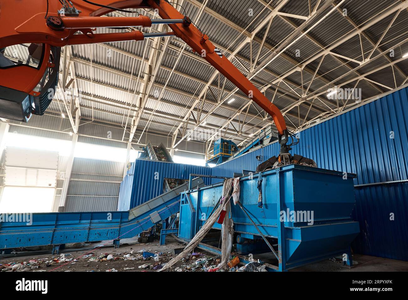 Grabbing excavator collects garbage in plant warehouse Stock Photo - Alamy