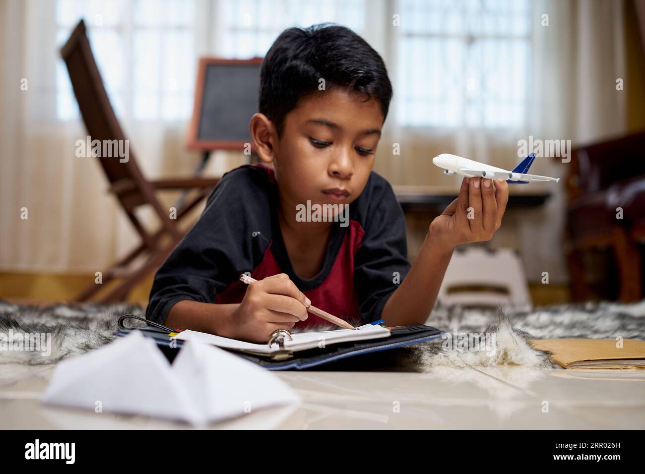 Schoolboy playing airplane toy while doing homework Stock Photo - Alamy