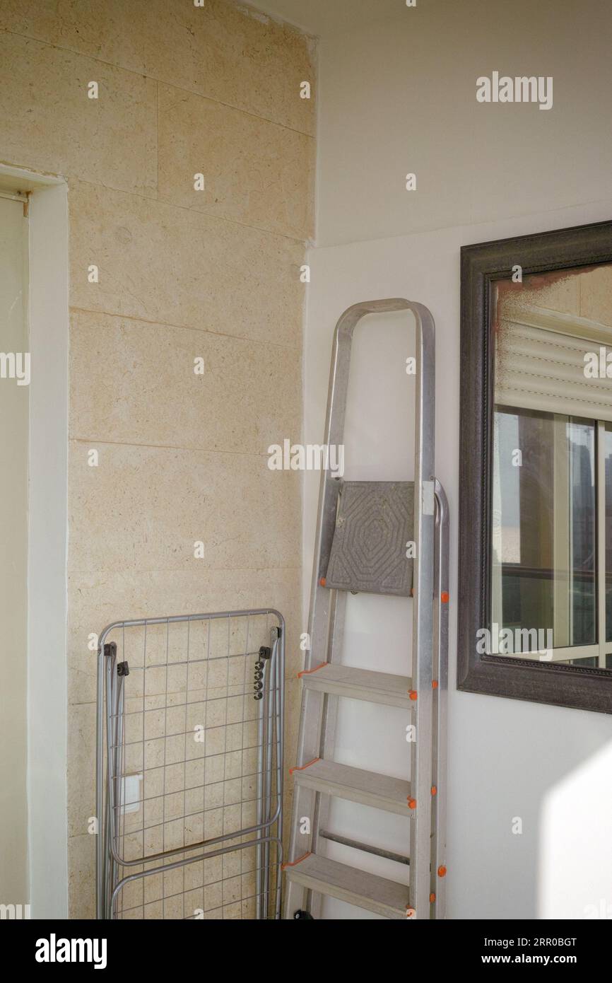 Vertical shot of a metal folding ladder and drying rack leaned against ...