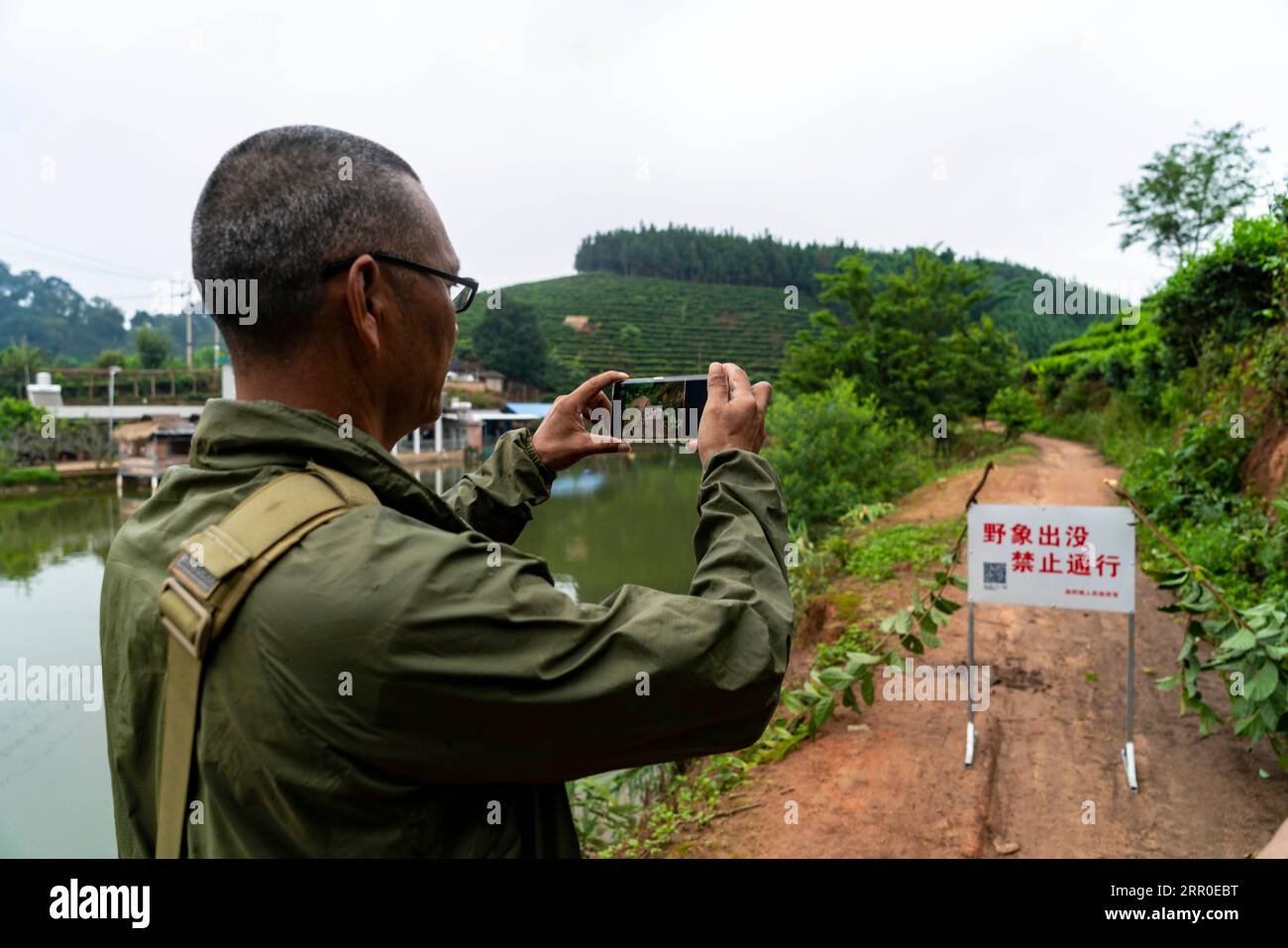 200811 -- XISHUANGBANNA, Aug. 11, 2020 -- Pu Zongxin takes a photo of a ...