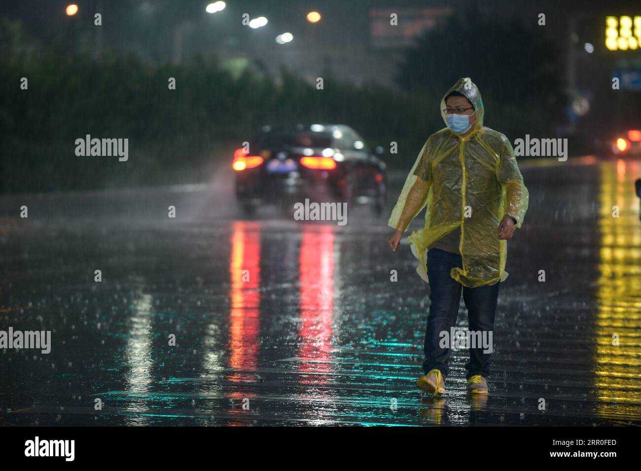 200812 -- BEIJING, Aug. 12, 2020 -- A man walks in rain in Daxing ...
