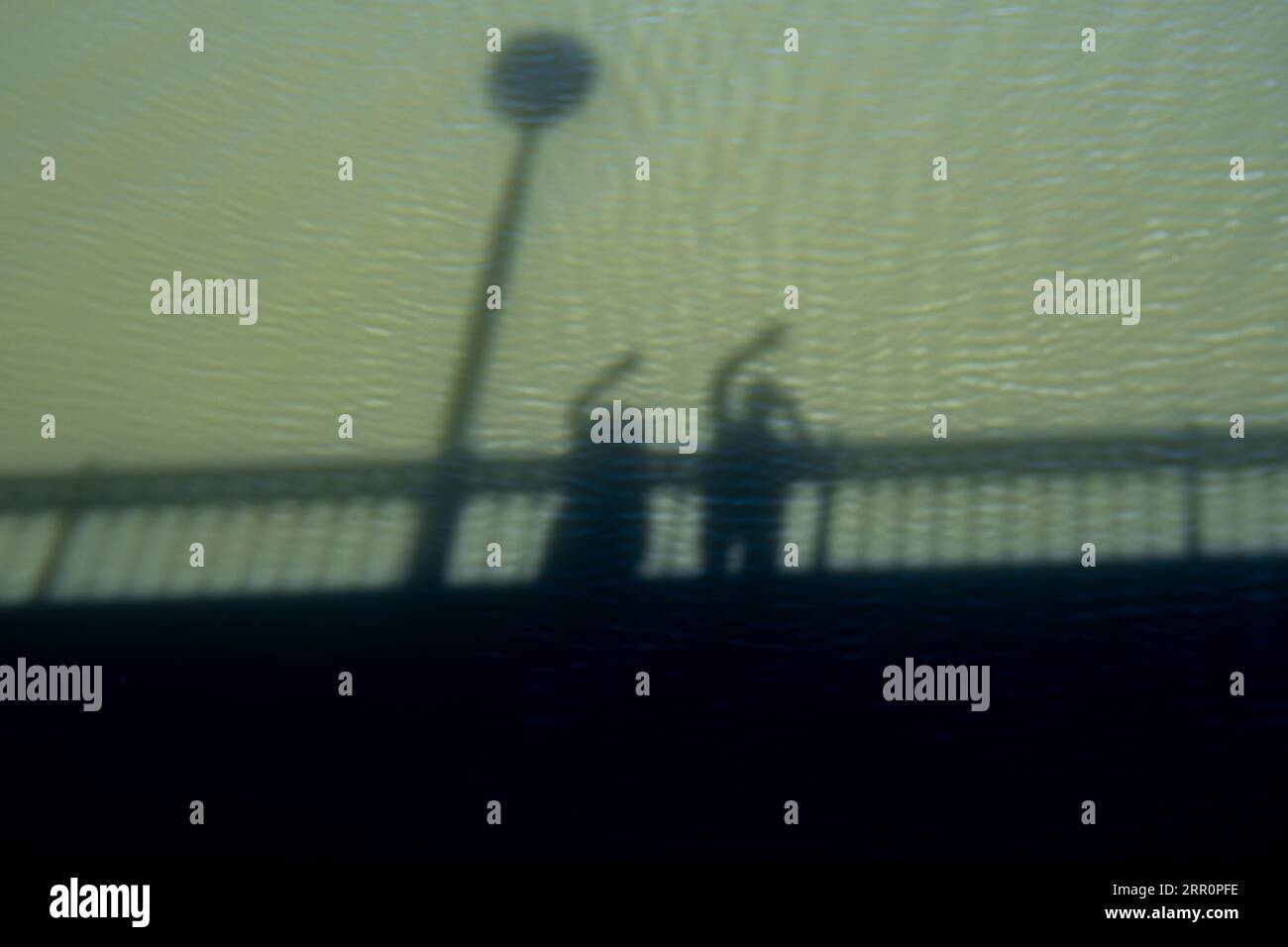 Shadow and silhouette of a bridge and a couple having a great time ...