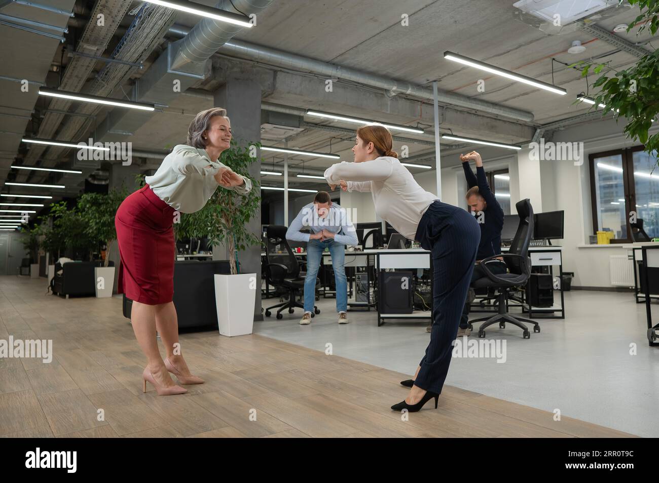 Four office workers warm up during a break. Employees do fitness ...