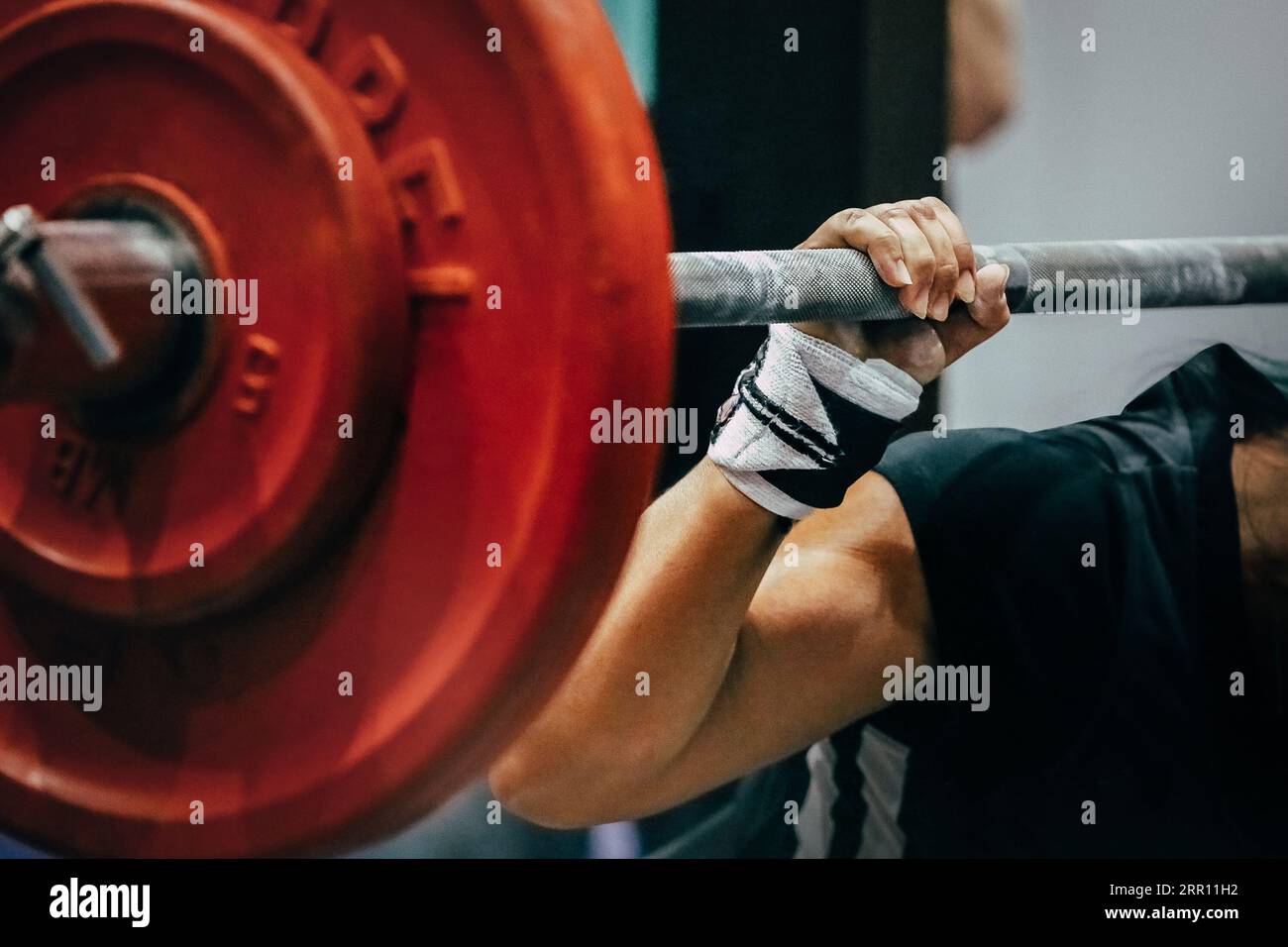 close-up red plates barbell and arm female powerlifter during squat ...