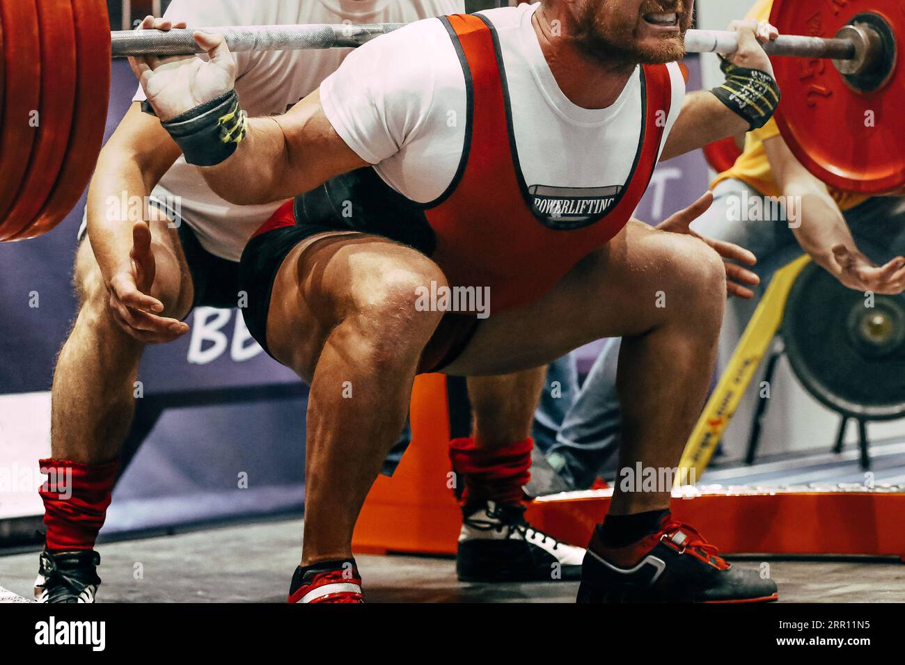 close-up male powerlift squat in powerlifting, coach hands are on ...