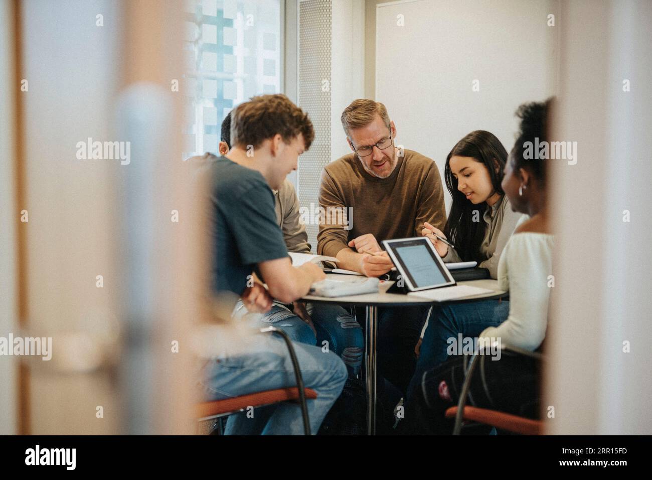 Mature male professor explaining students at table in university Stock ...