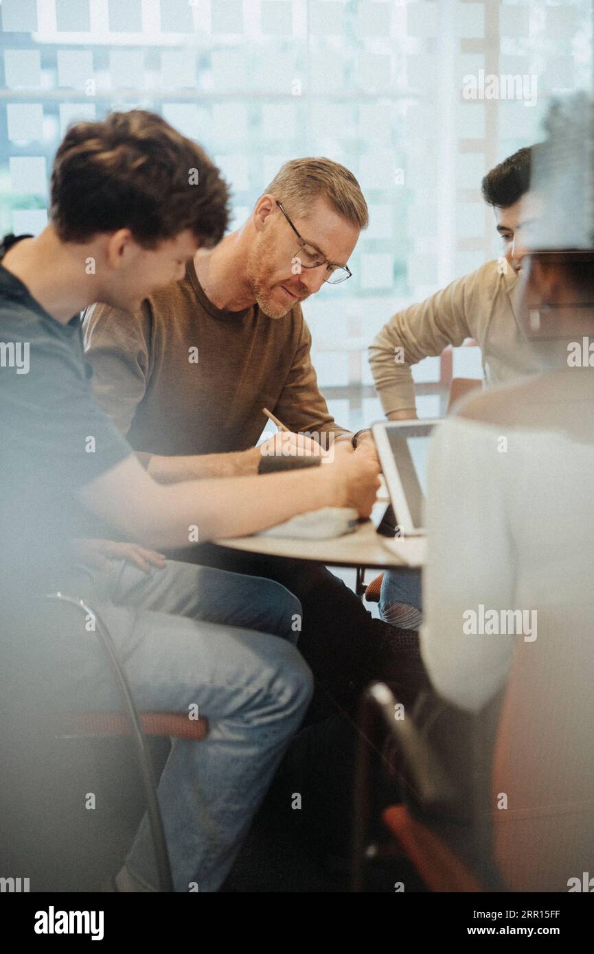 Mature professor assisting students in classroom at university Stock ...