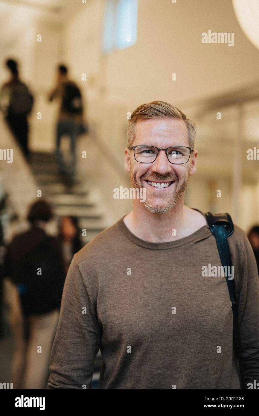 Portrait of happy mature male professor standing in university Stock ...