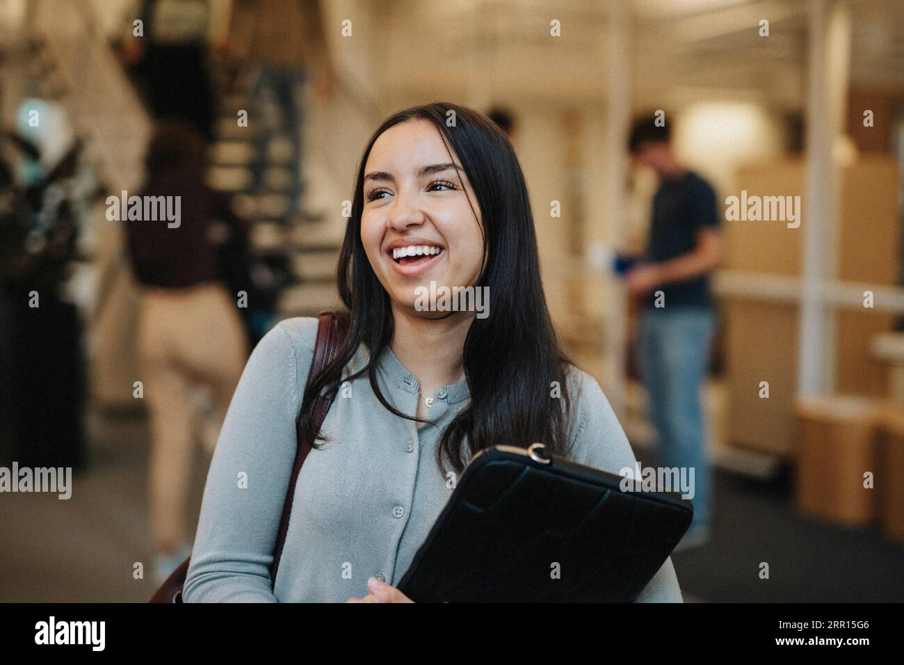 Cheerful female student carrying file folder at university Stock Photo ...